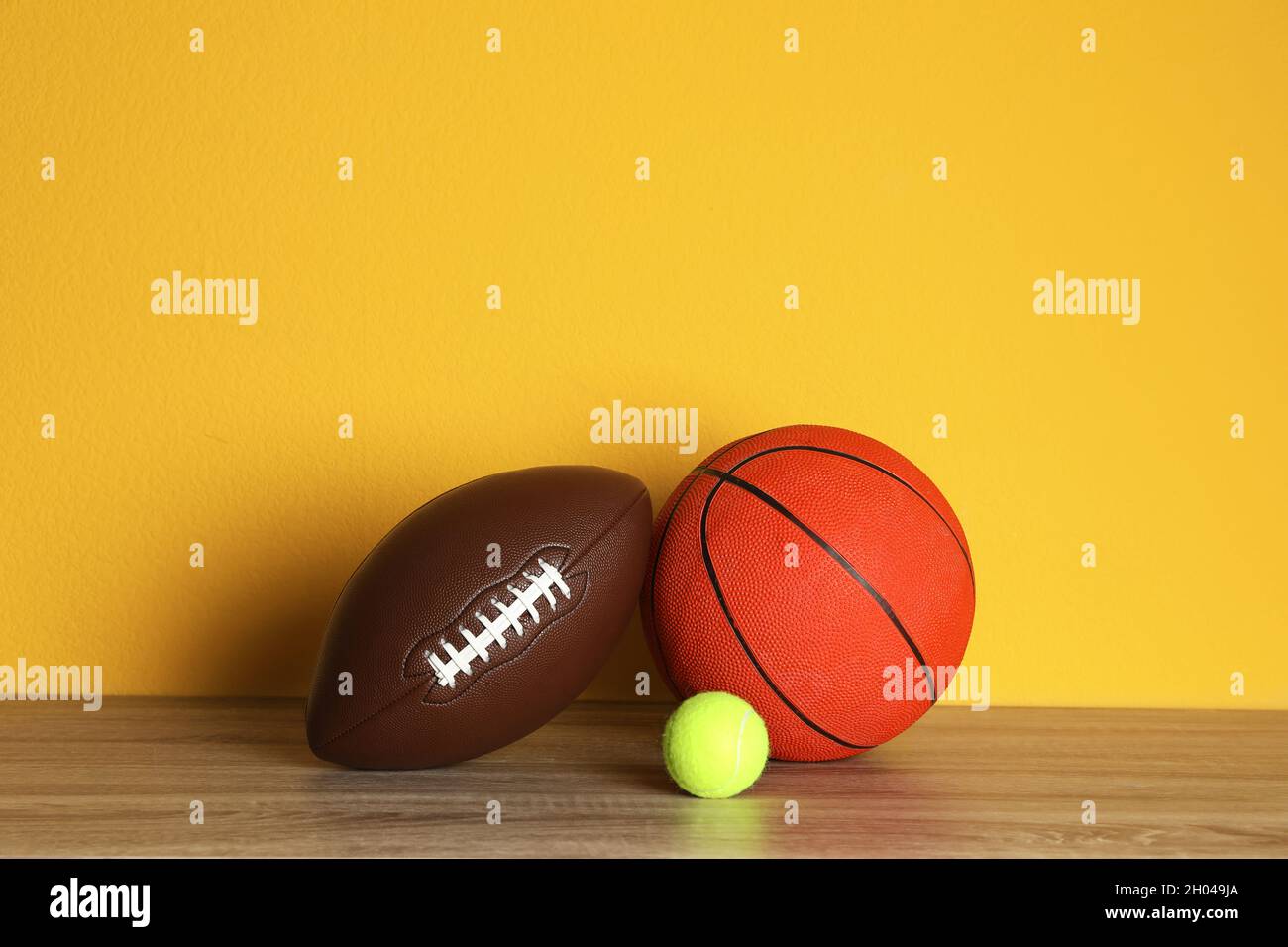 Different sport balls on table against color background. Space for text ...