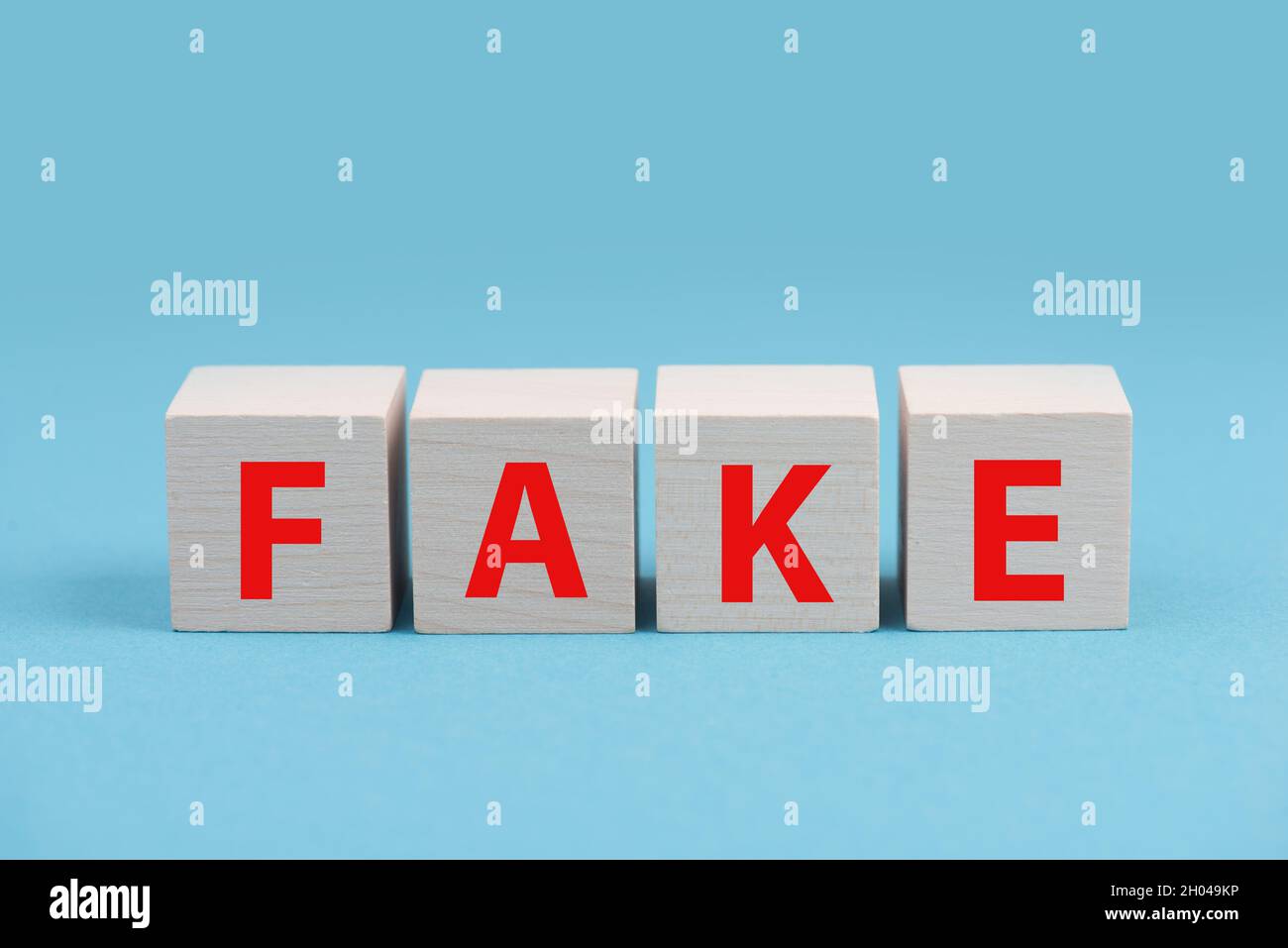 The word fake is standing in red color on wooden cubes, blue background ...