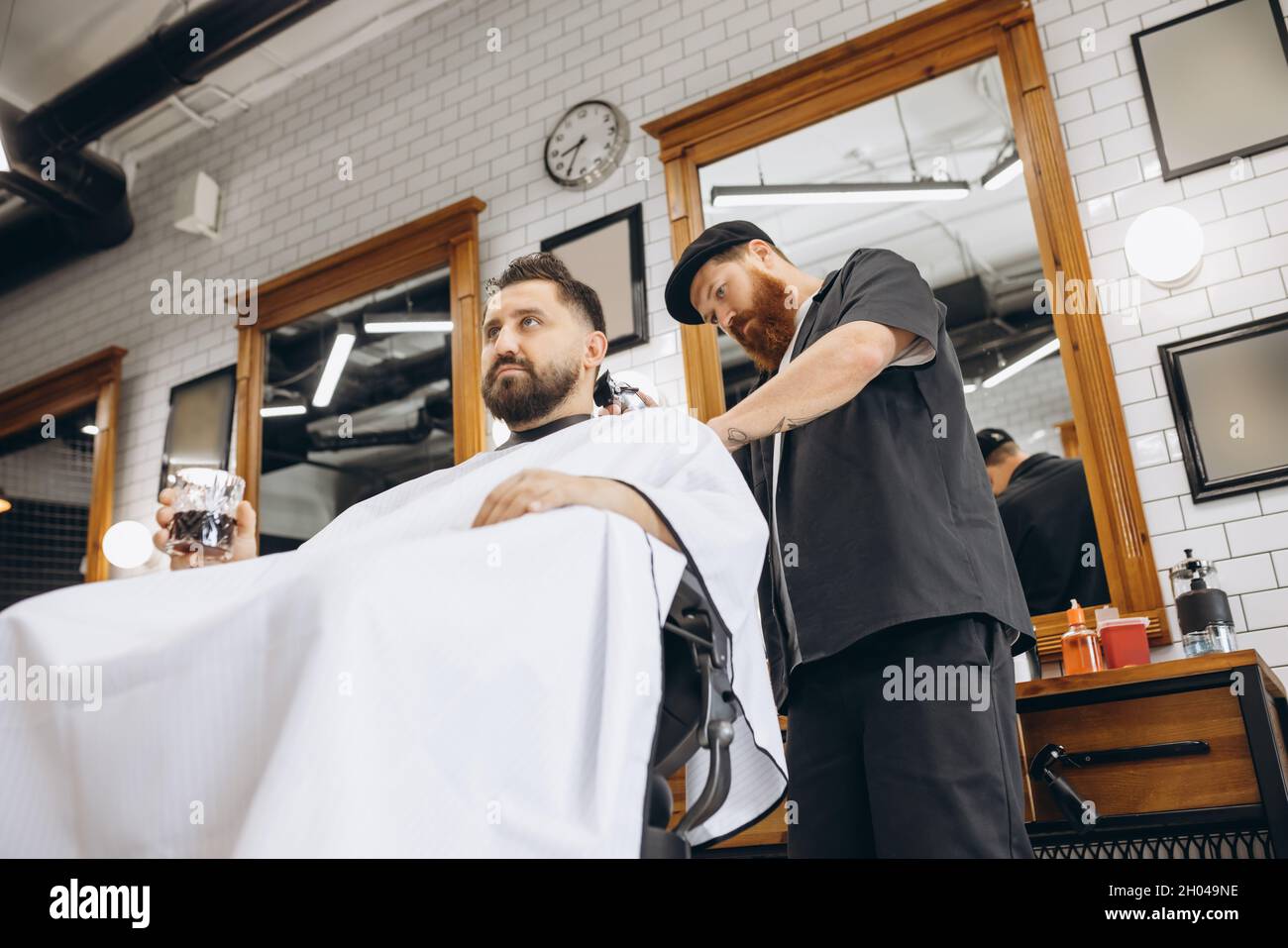 Two handsome men at barbershop. Stylish red-bearded barber and client ...