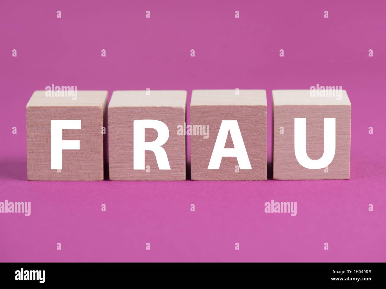 The word woman is standing in german language on wooden cubes, pink ...