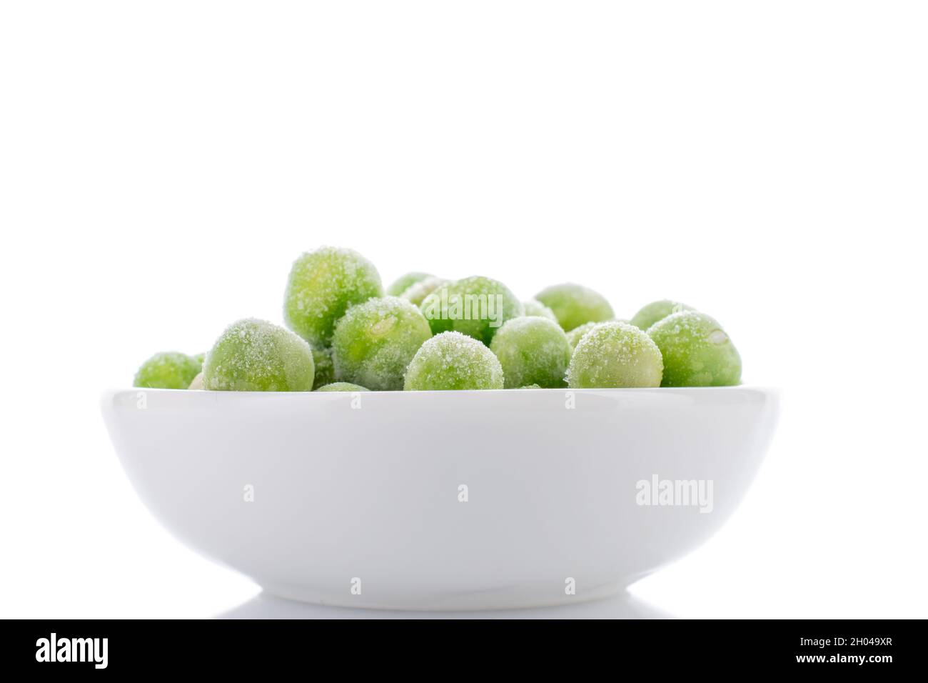 Organic frozen green peas in a white plate, close-up, isolated on white ...