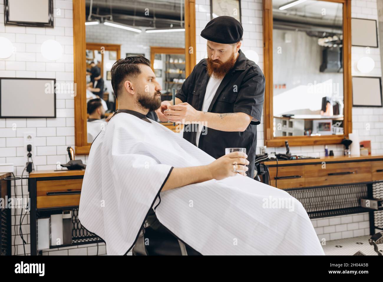 Two handsome men at barbershop. Stylish red-bearded barber and client ...