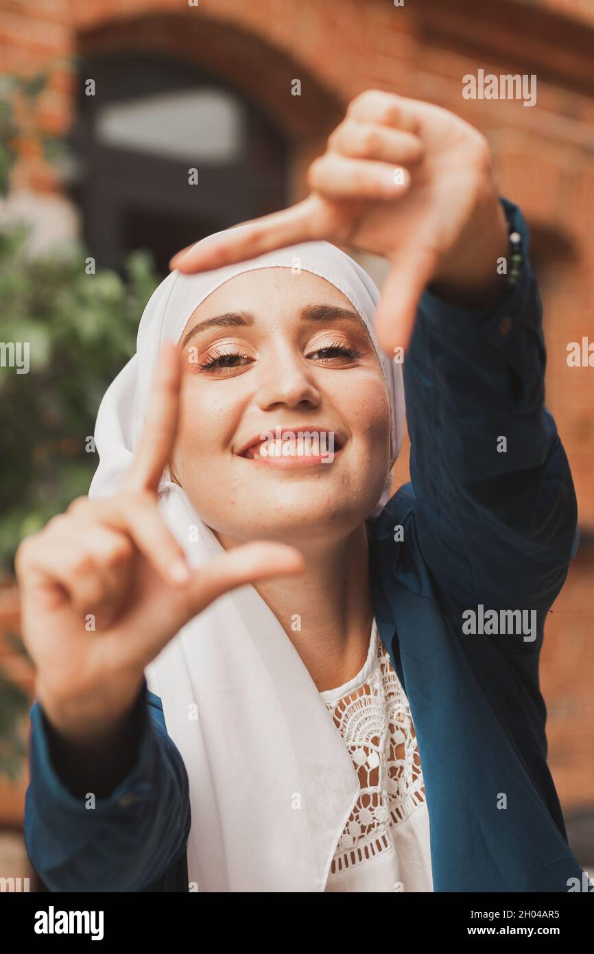 Portrait of young muslim girl making a camera frame with fingers ...