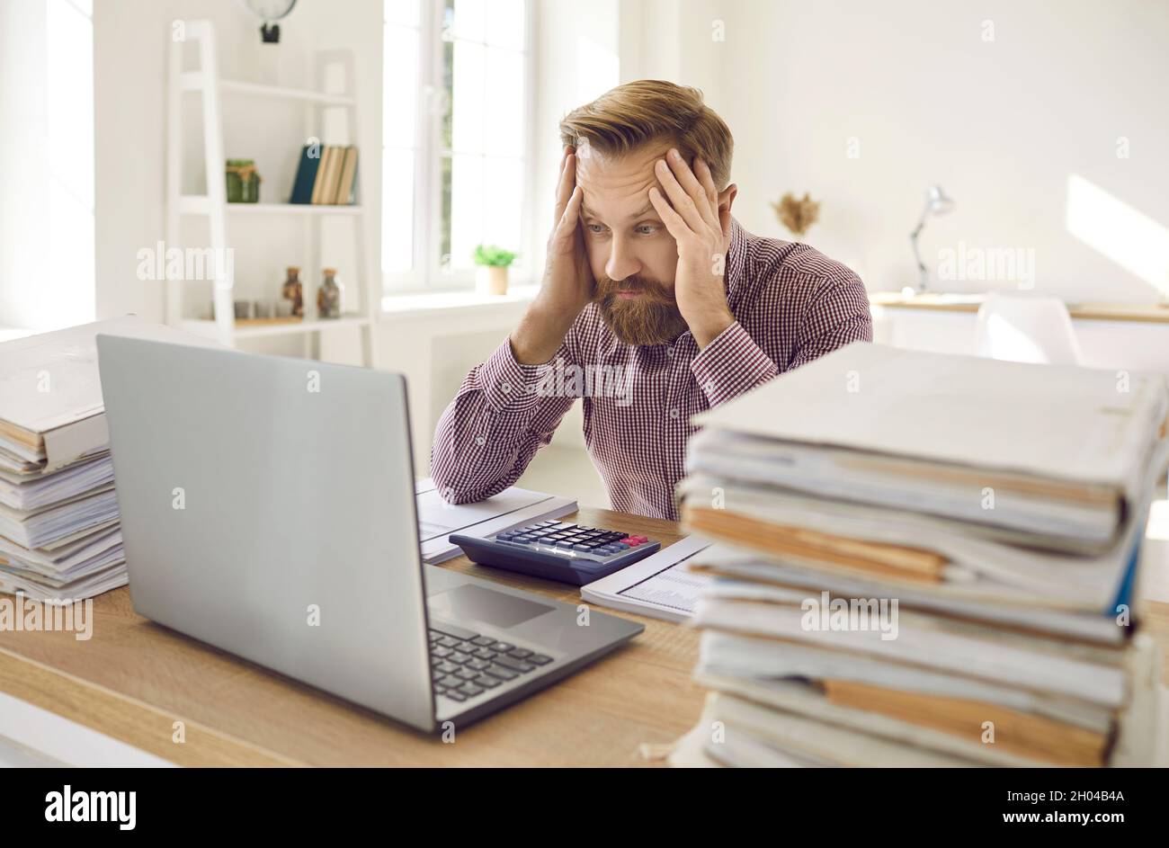 Tired exhausted male office worker working all day on financial report ...