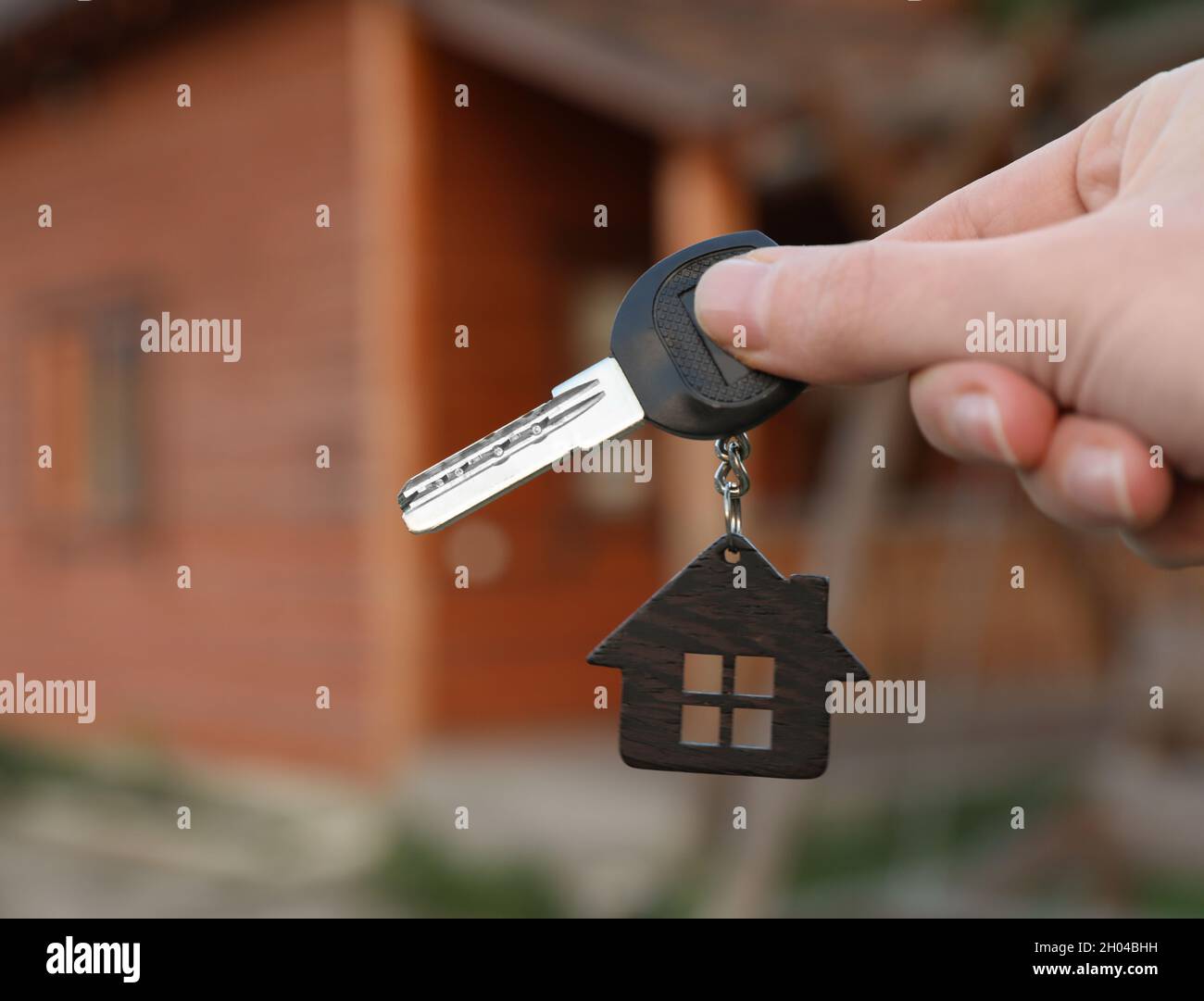 Real estate agent holding key and blurred house on background. Focus on ...