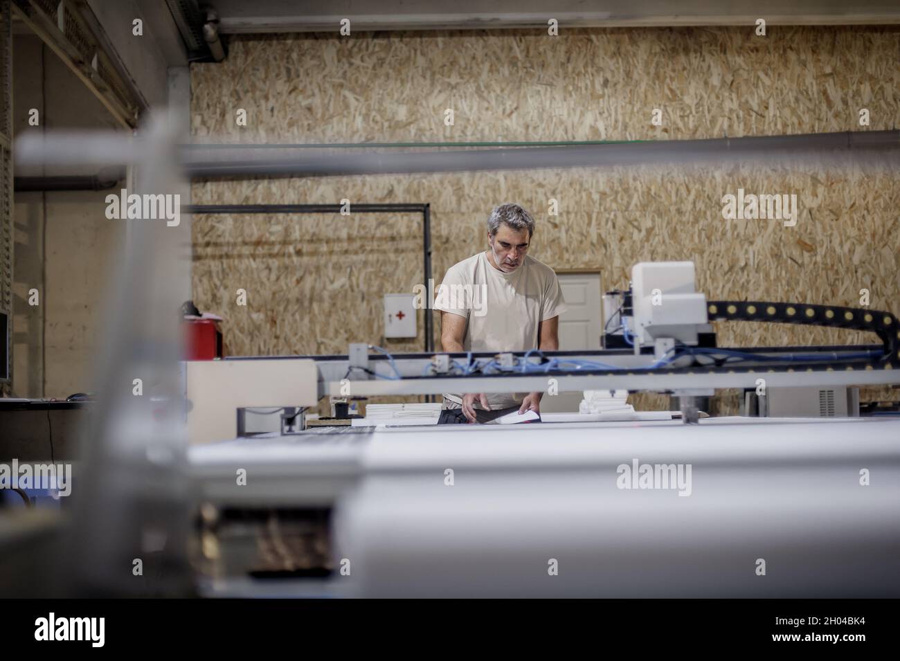 Factory worker technician works on large CNC digital cutter machine for ...