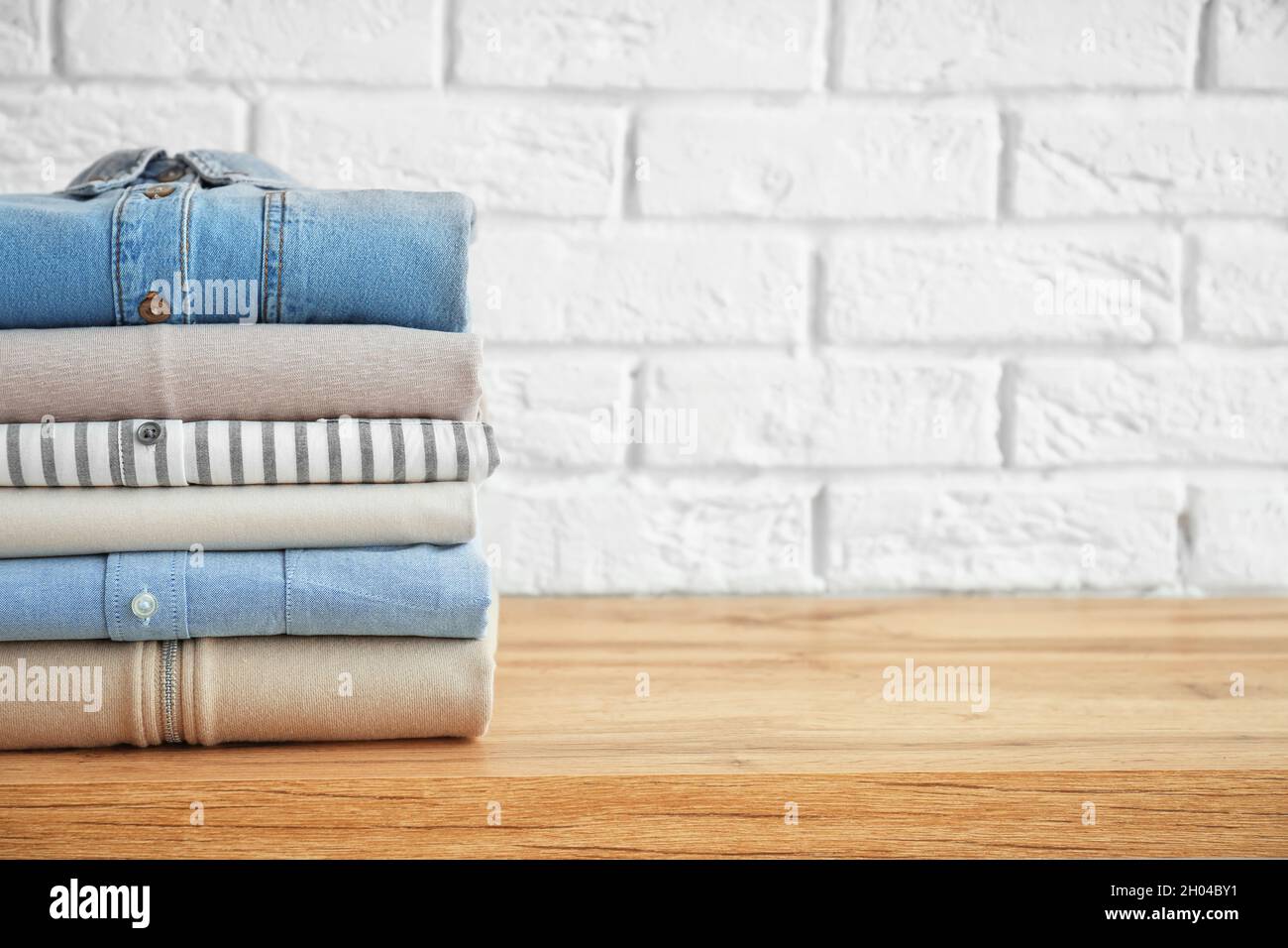 Stack of clothes on table near brick wall Stock Photo - Alamy