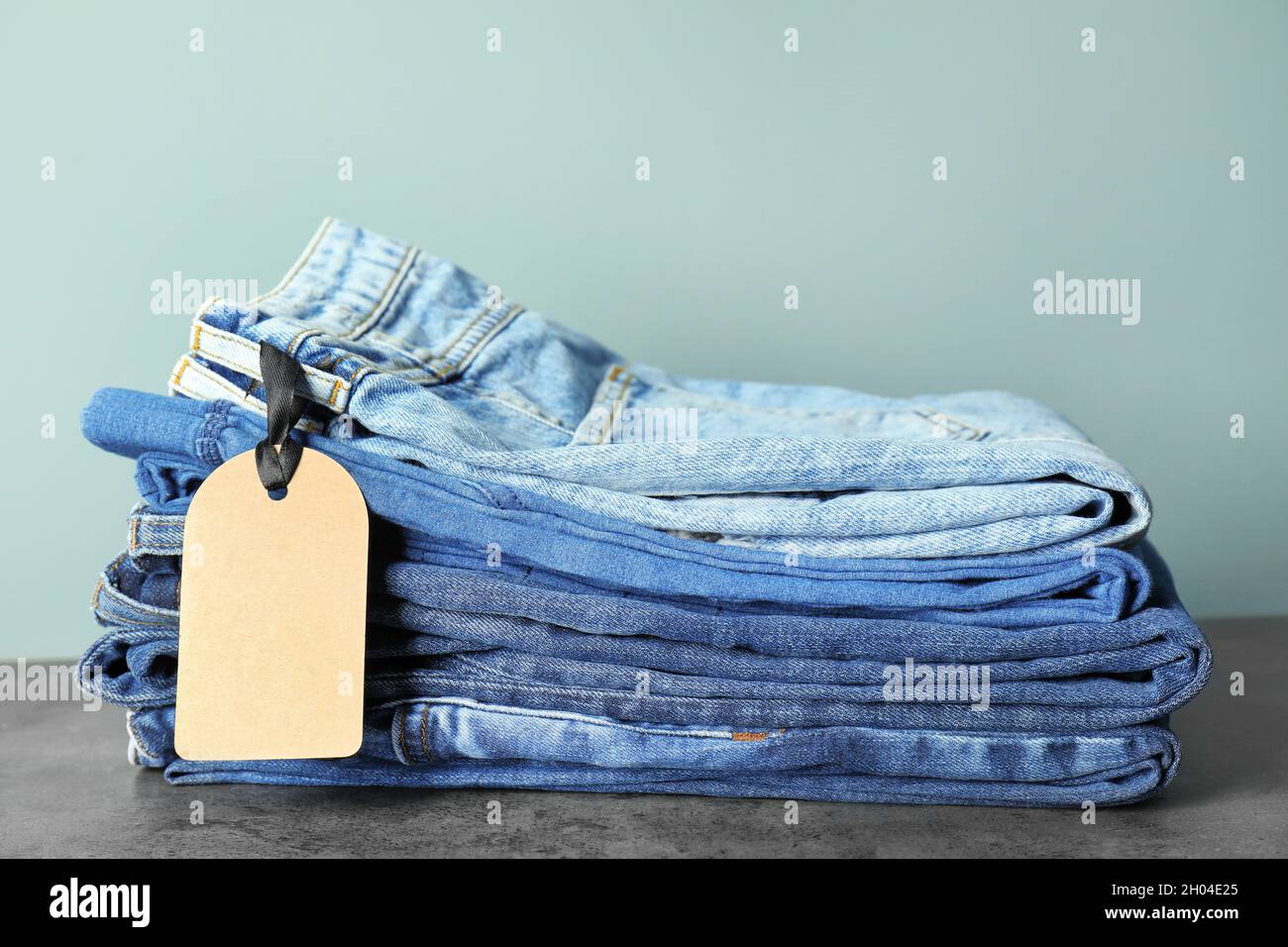 Stack of jeans on table against color background Stock Photo - Alamy