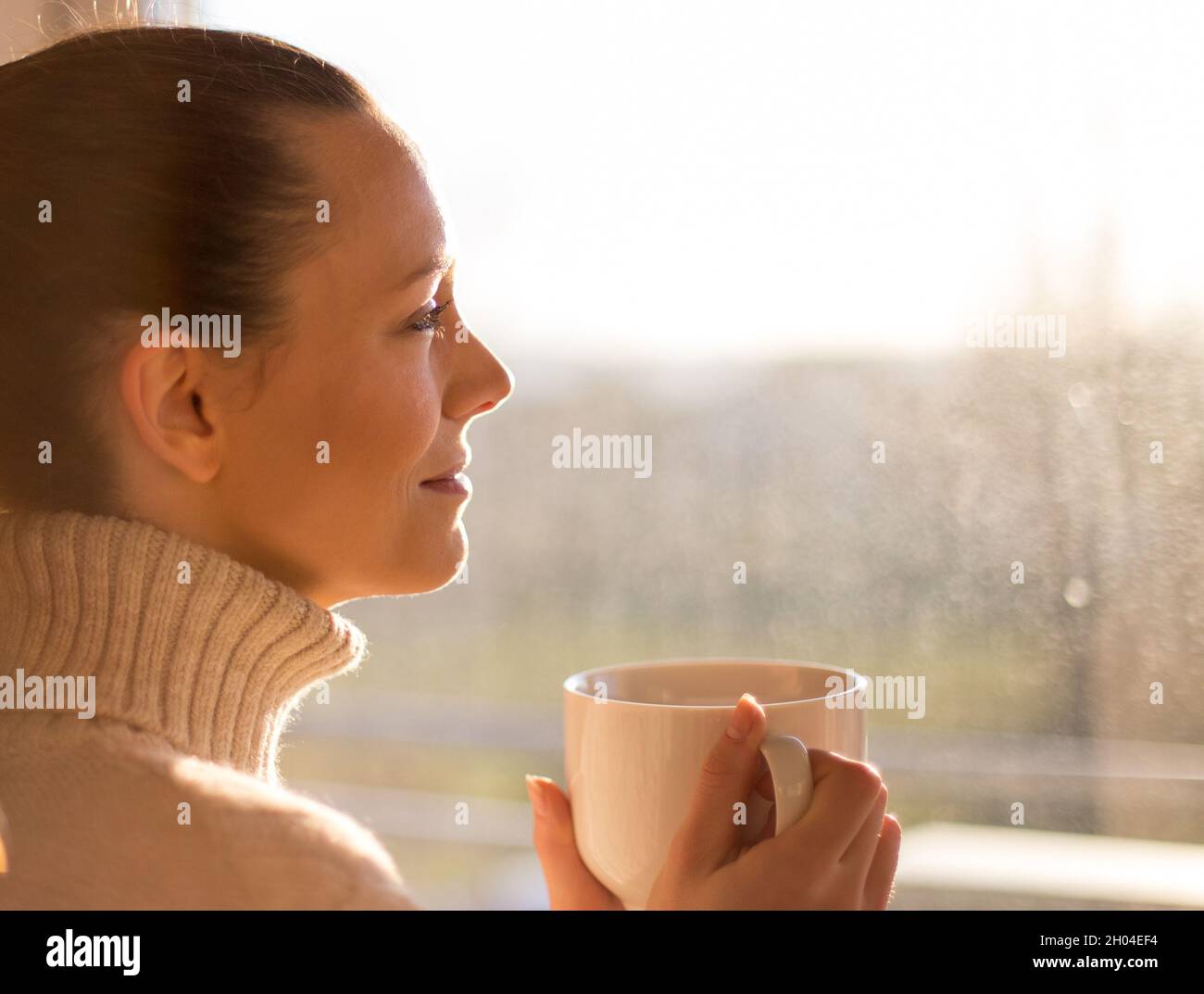 Pretty girl drinking hot coffee beside window at sunrise Stock Photo ...
