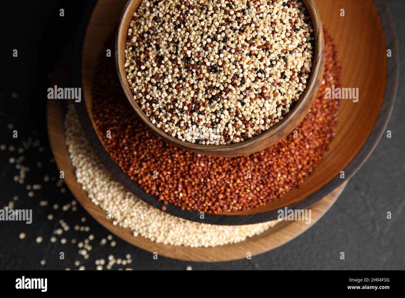Composition with different types of quinoa on black background, top ...