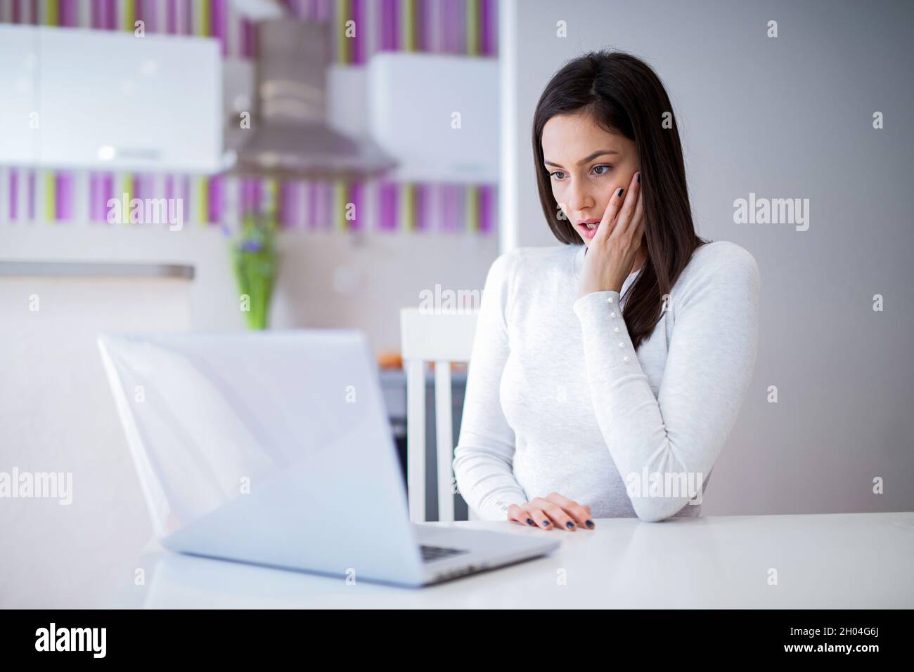 Young girl looking at laptop with confused look Stock Photo - Alamy