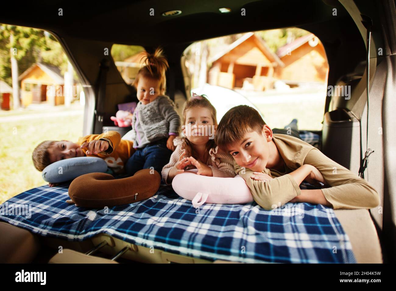 Family of four kids at vehicle interior. Children in trunk. Traveling ...