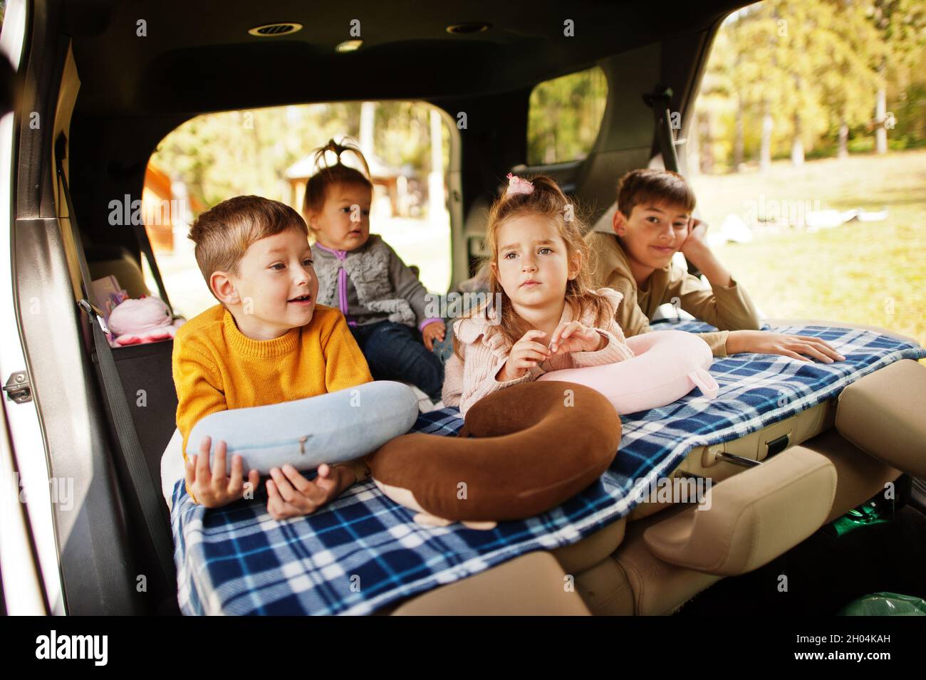 Family of four kids at vehicle interior. Children in trunk. Traveling ...