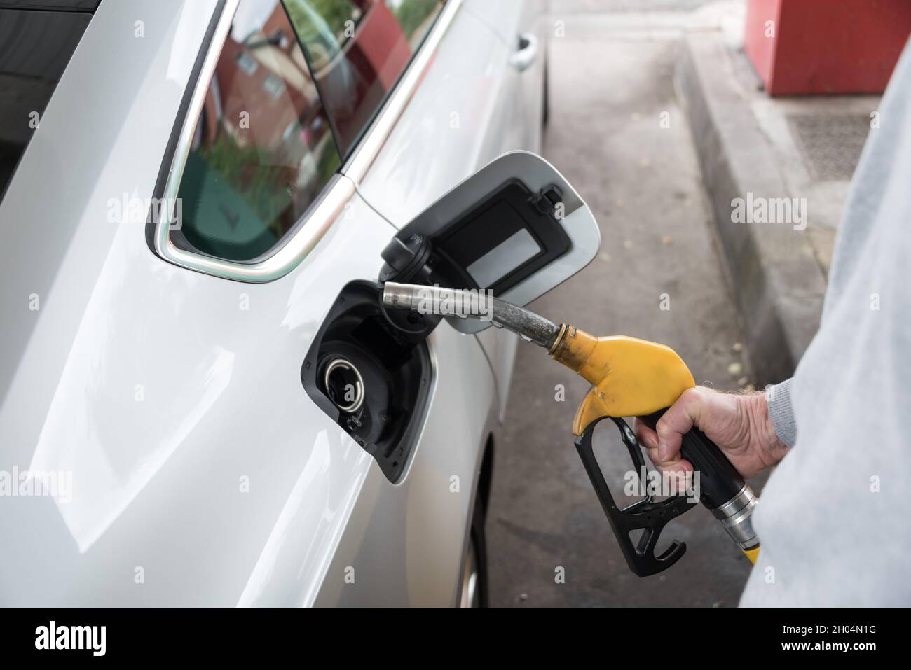 Man holding a yellow fuel pump nozzle Stock Photo - Alamy