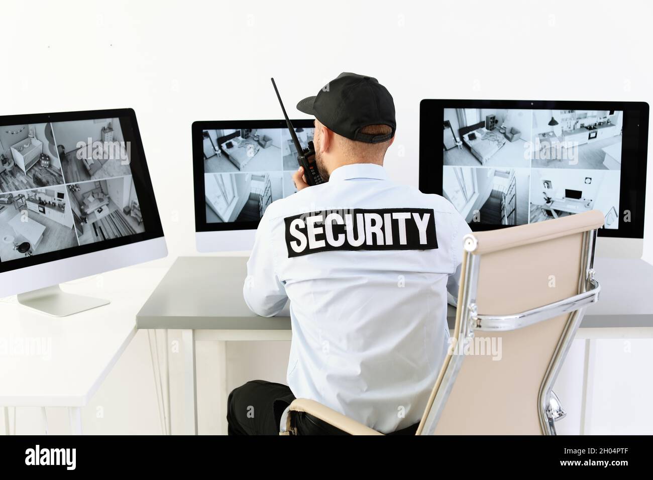 Male security guard with portable transmitter monitoring home cameras ...