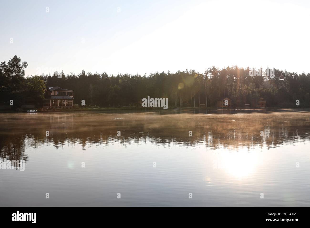 Beautiful landscape with forest and houses near lake. Camping season ...