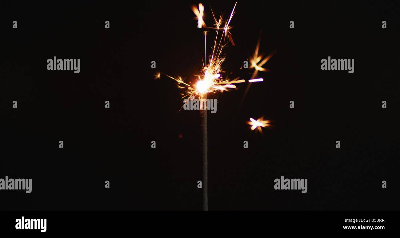 Lit party sparkler sparkling on black background Stock Photo - Alamy