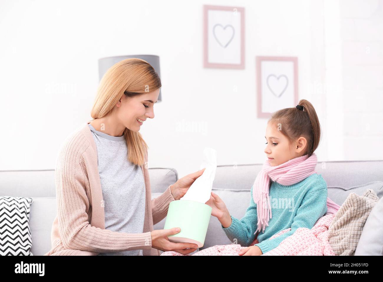 Mother giving daughter paper tissue on sofa at home Stock Photo - Alamy