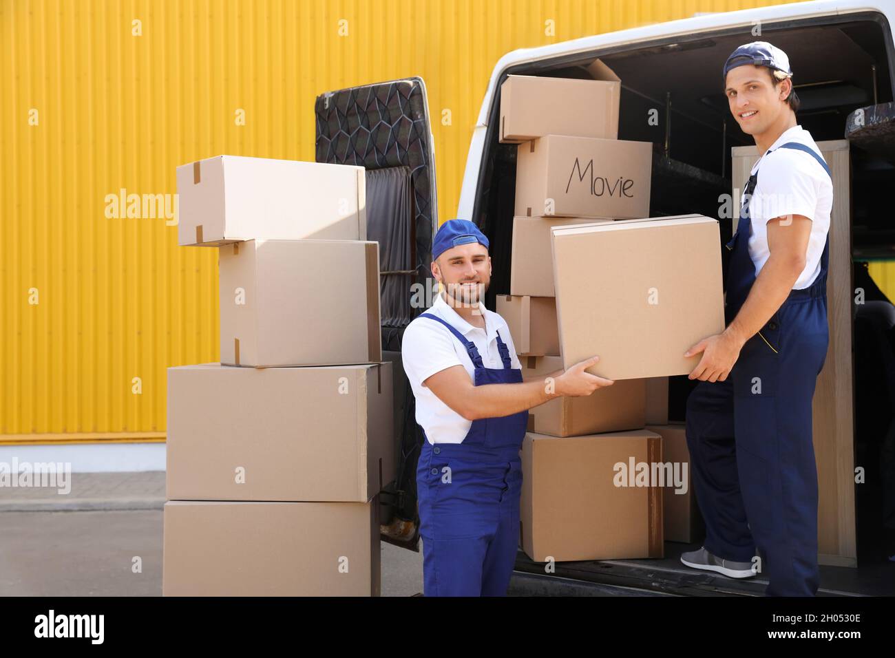 Male movers unloading boxes from van outdoors Stock Photo - Alamy