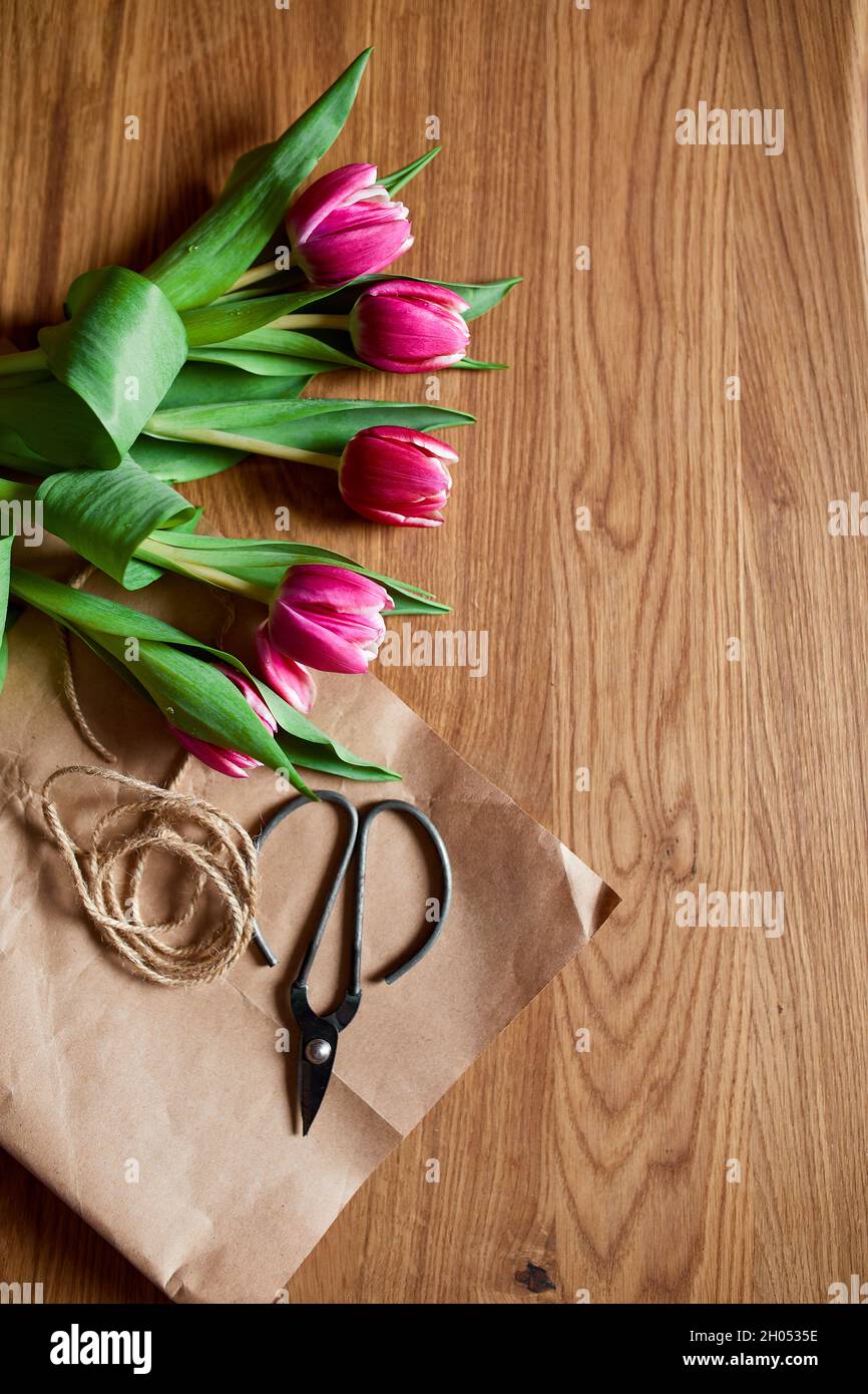 Floristic workplace with craft paper, twine Arranging pink tulips ...