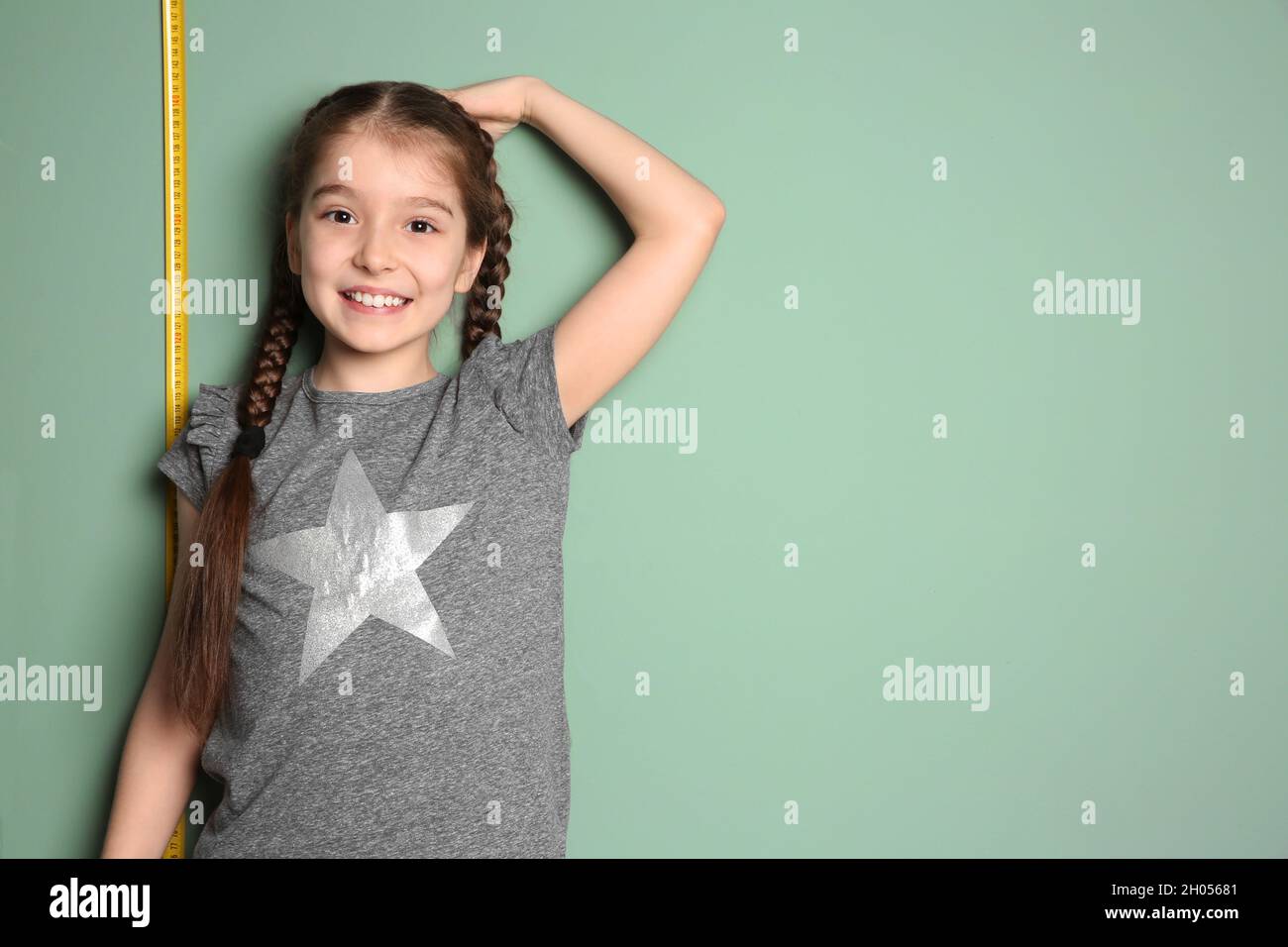 Little girl measuring her height on color background Stock Photo - Alamy