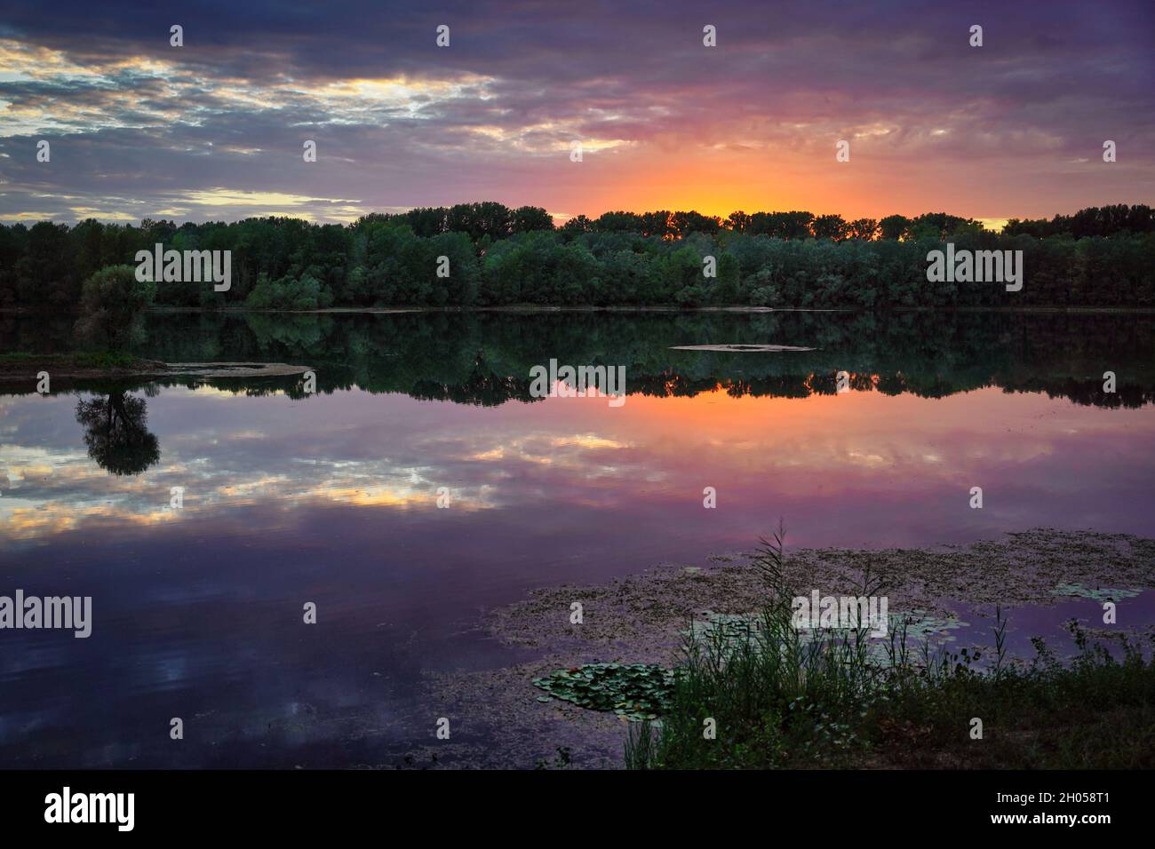 A beautiful sunset at a lake. Orange and purple clouds reflecting in the water. Long exposure ...