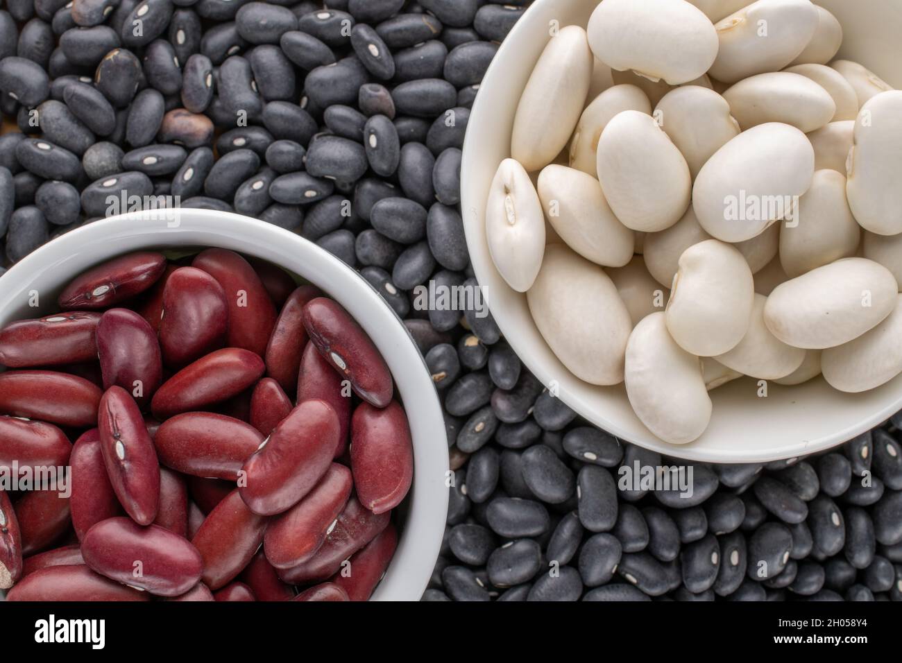 Three kinds of organic red, white, black dried beans in ceramic saucers ...