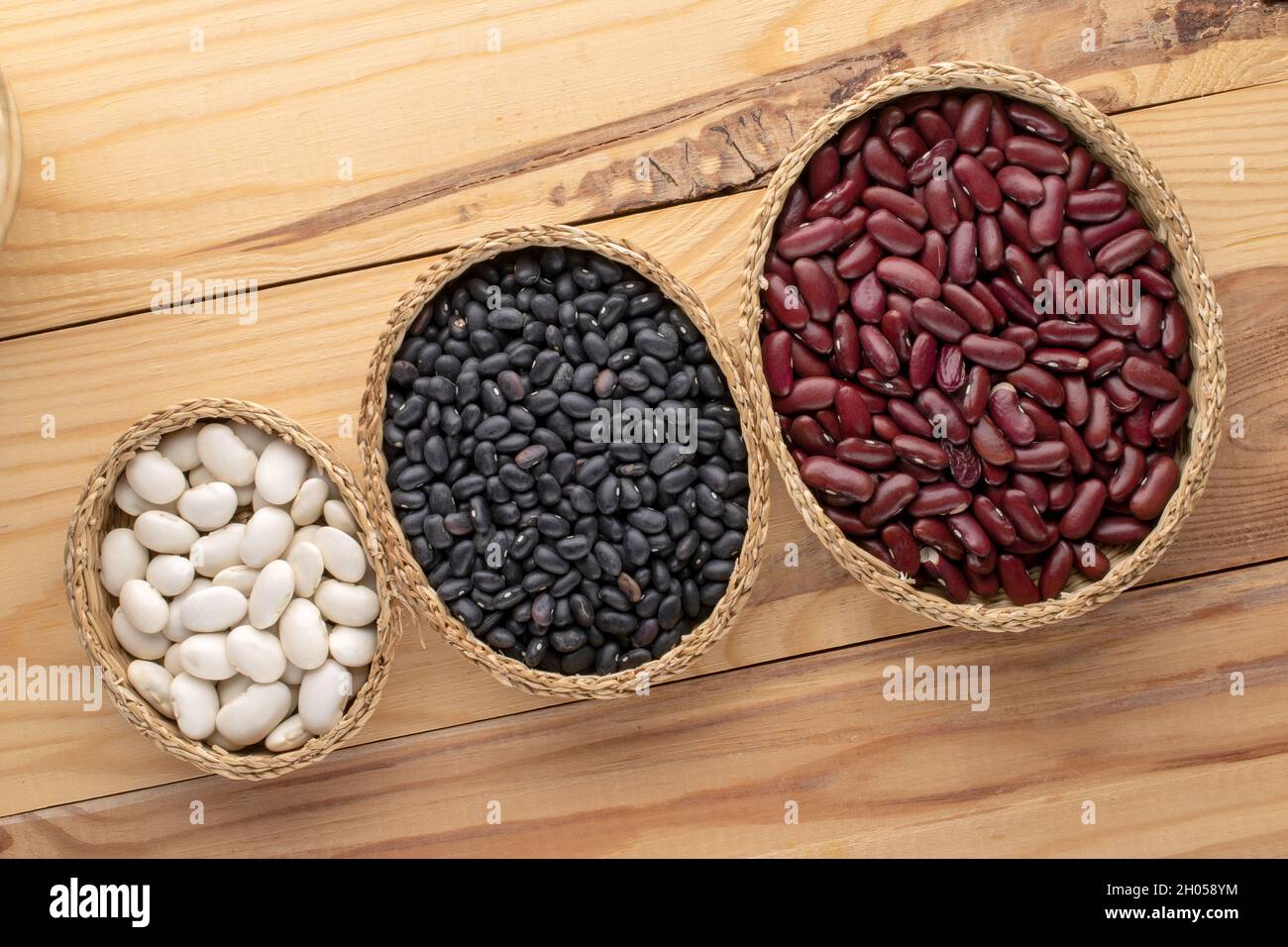 Three kinds of organic red, white, black dried beans in straw plates ...