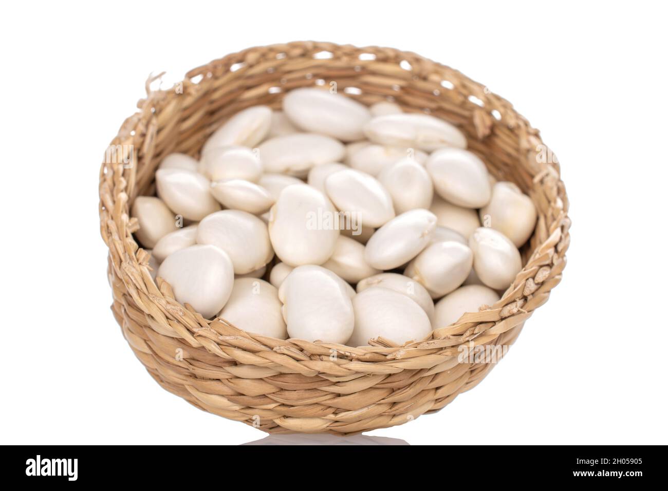 Uncooked organic, white dried beans in a straw plate, close-up ...