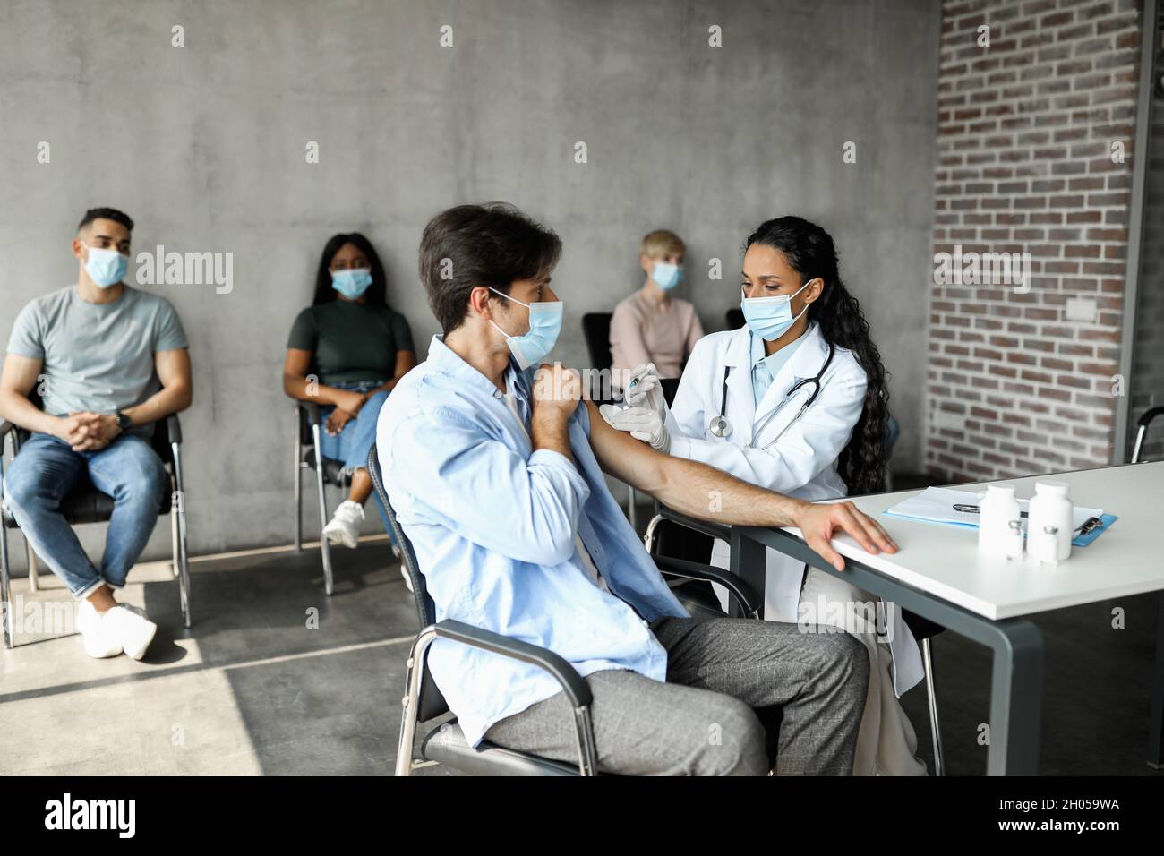 Male patient getting intramuscular shot against COVID-19 at clinic or ...