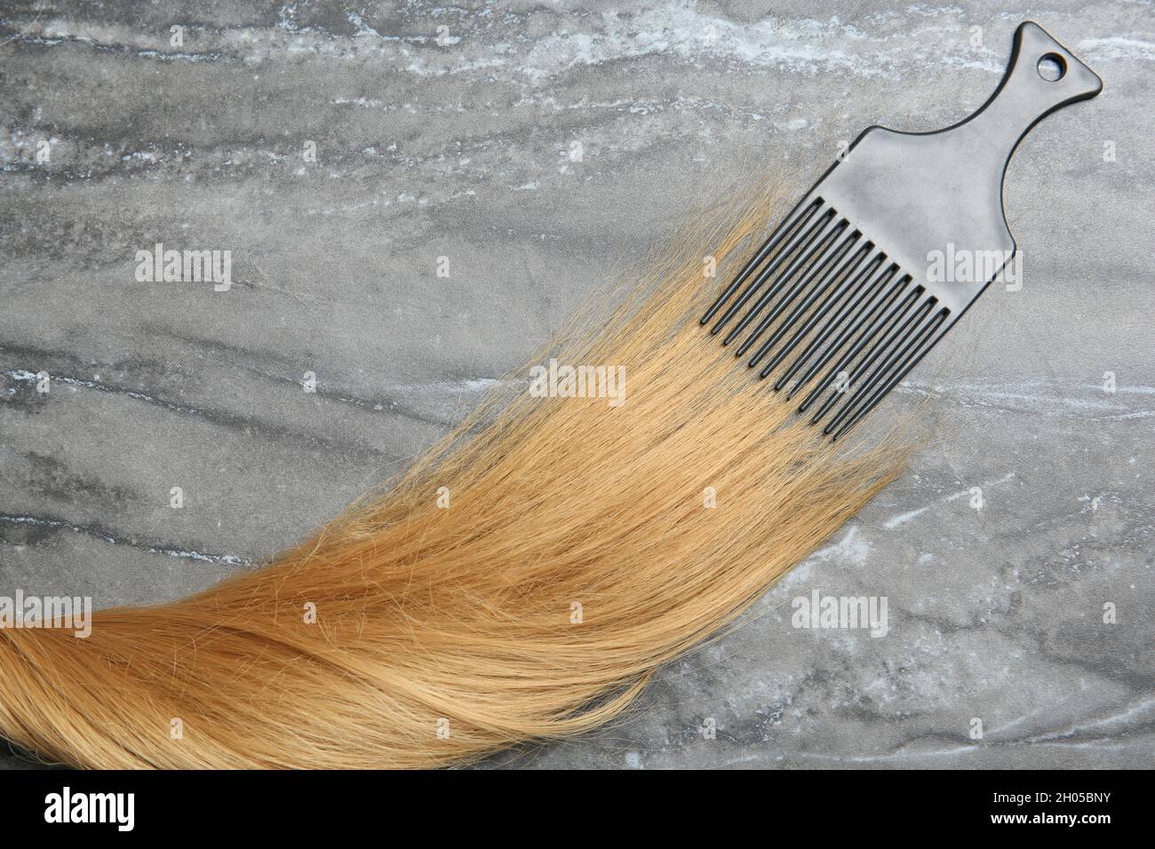 Flat lay composition with strand of hair and comb on grey background ...