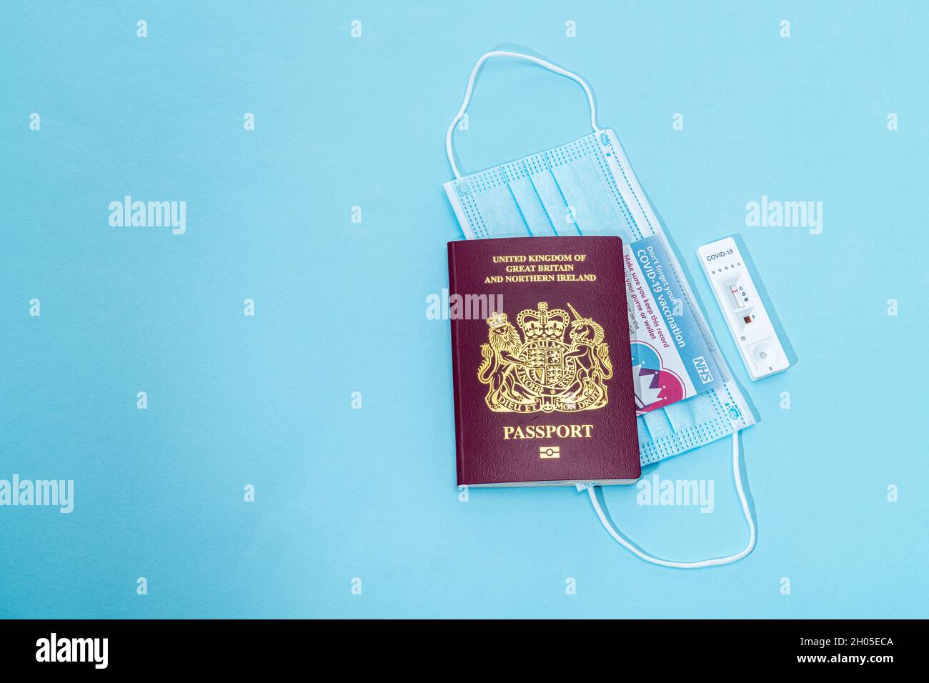 Travel documents with a passport, face mask, NHS vaccination card and ...