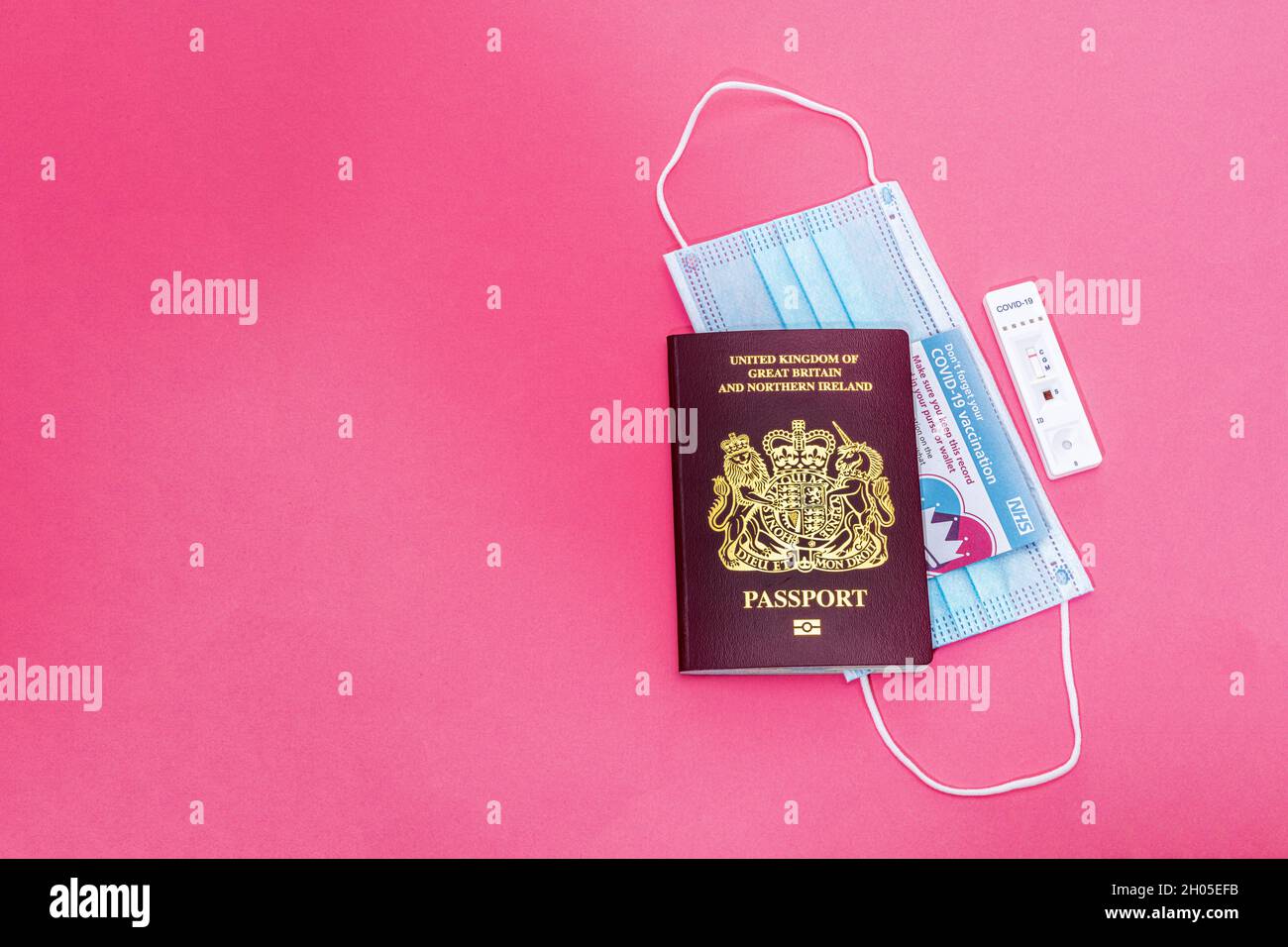 Travel documents with a passport, face mask, NHS vaccination card and ...