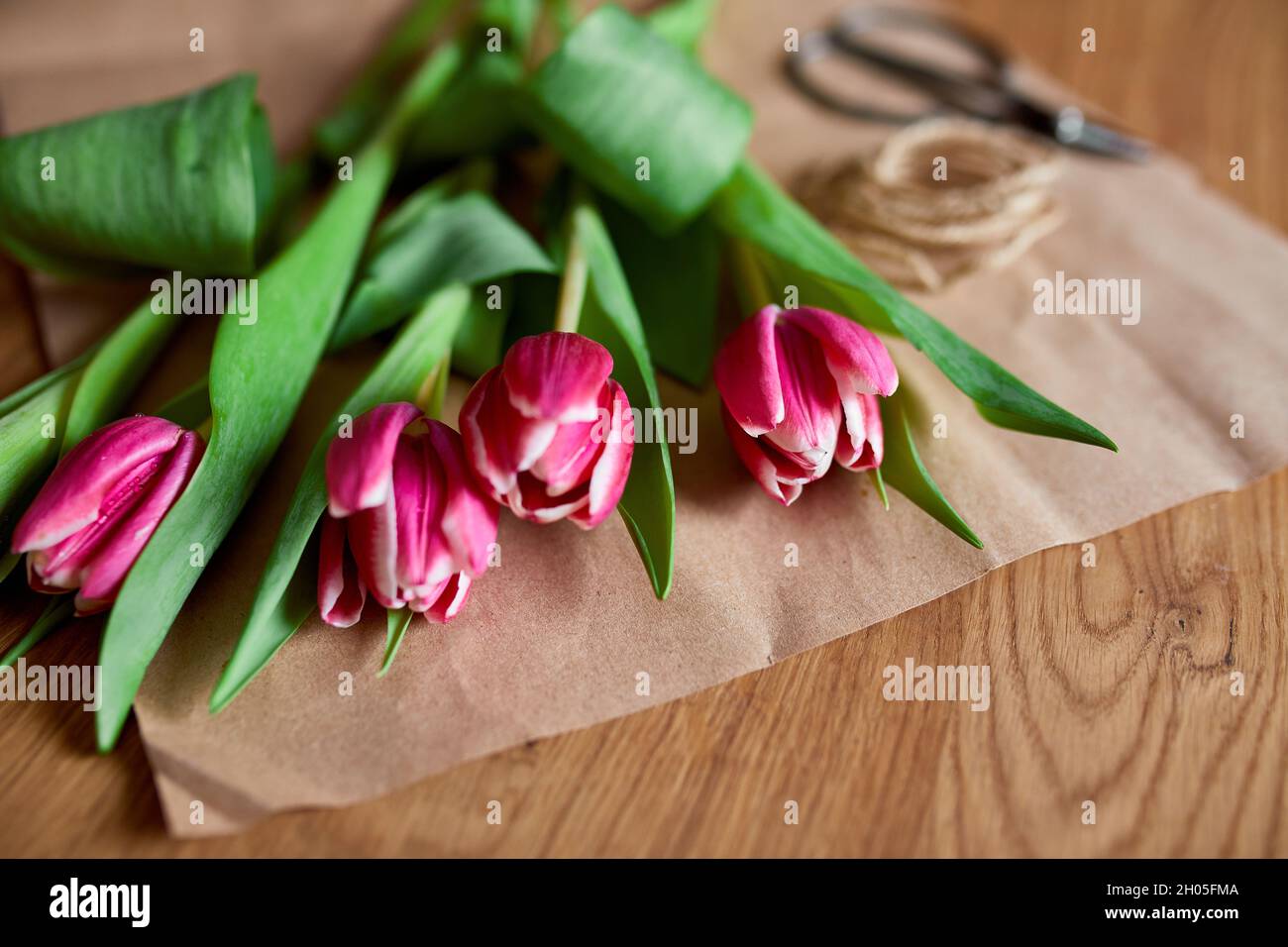 Floristic workplace with craft paper, twine Arranging pink tulips ...