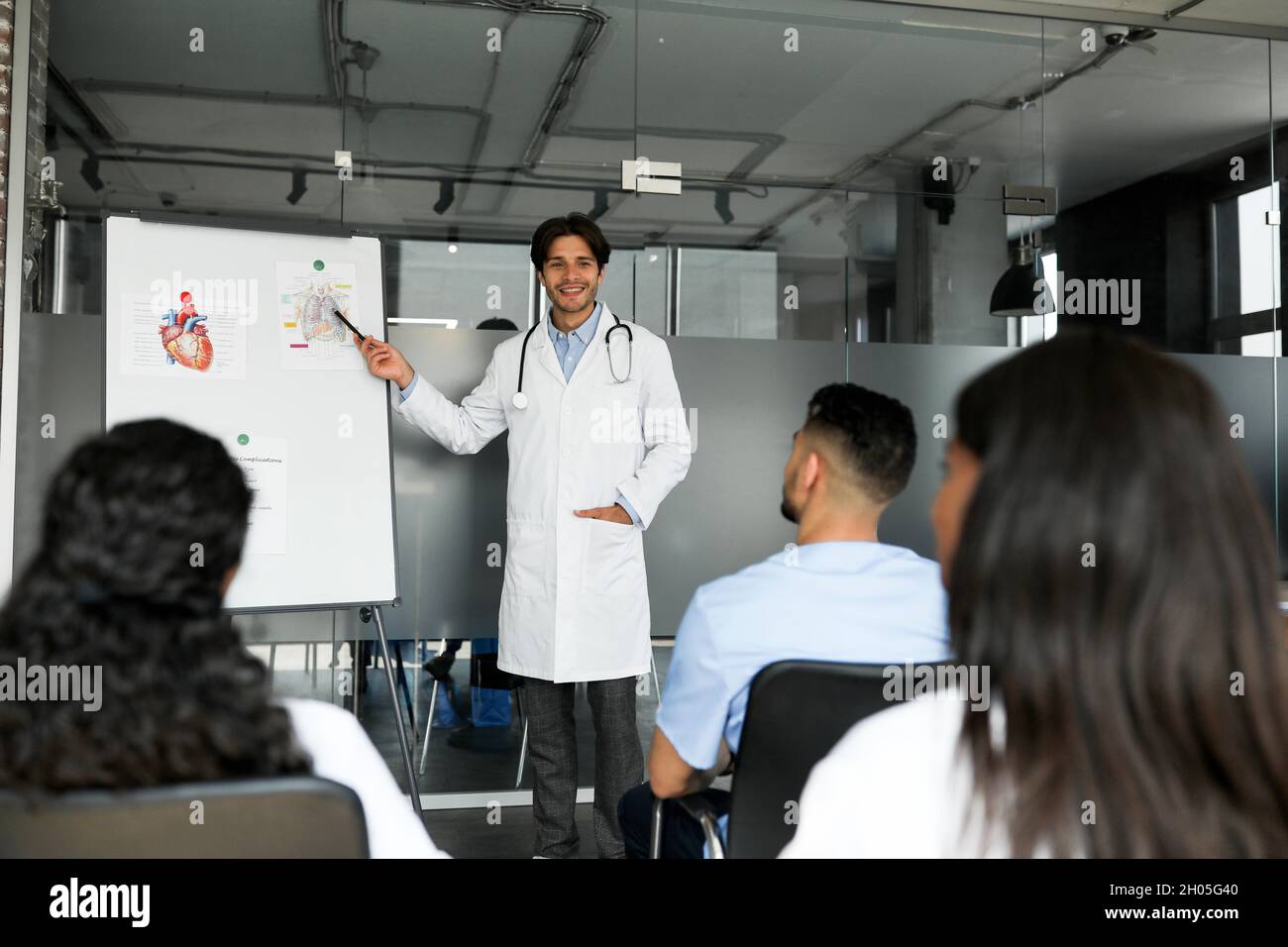 Cheerful young man chief doctor standing by presentation board, having ...