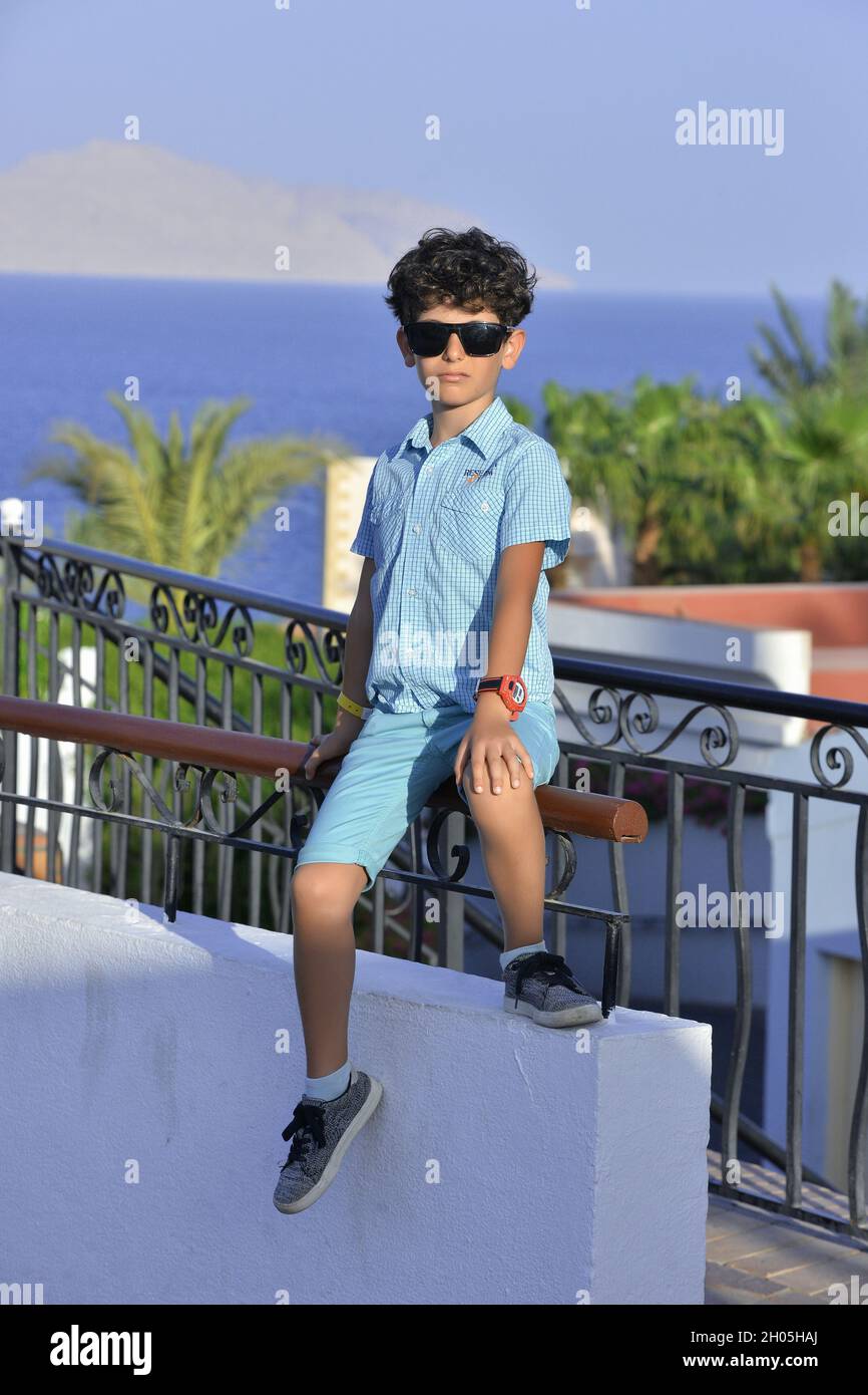 Full body shot of an Armenian boy wearing sunglasses sitting on the ...