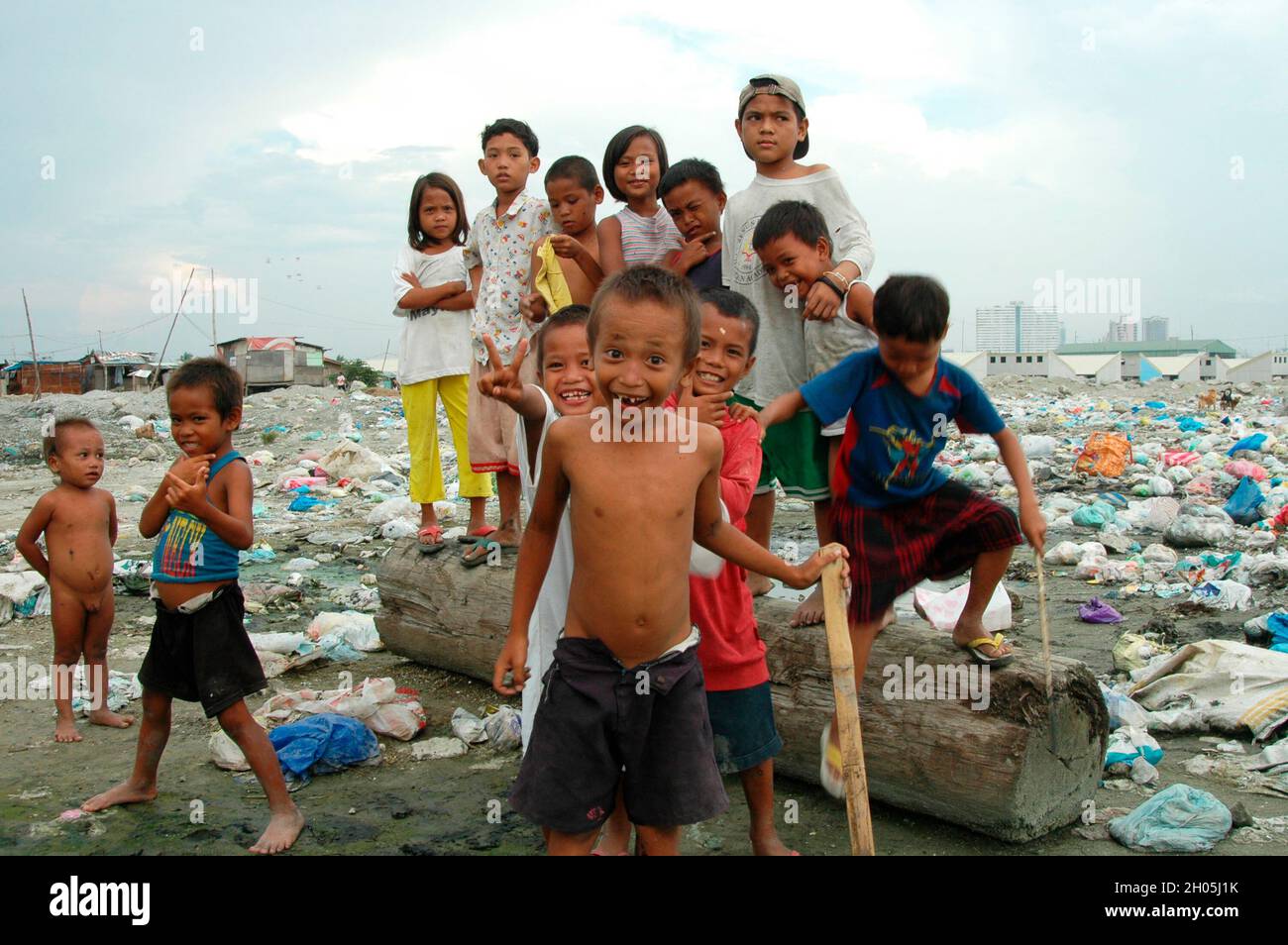 Children in Baseco pose for a picture on top of a log with garbage in ...