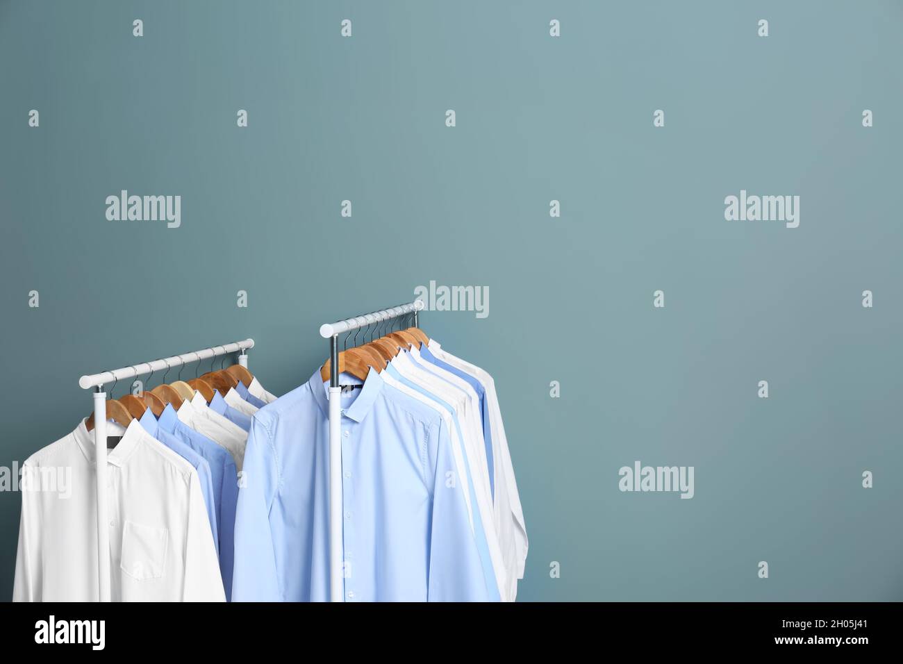 Racks with clean clothes after dry-cleaning against color background ...