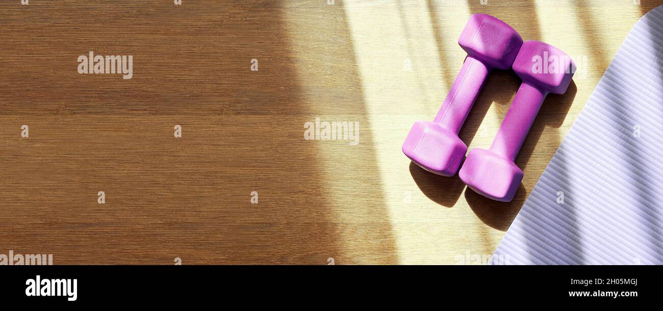Pink fitness dumbbell and mat in the sports gym on the wooden floor ...