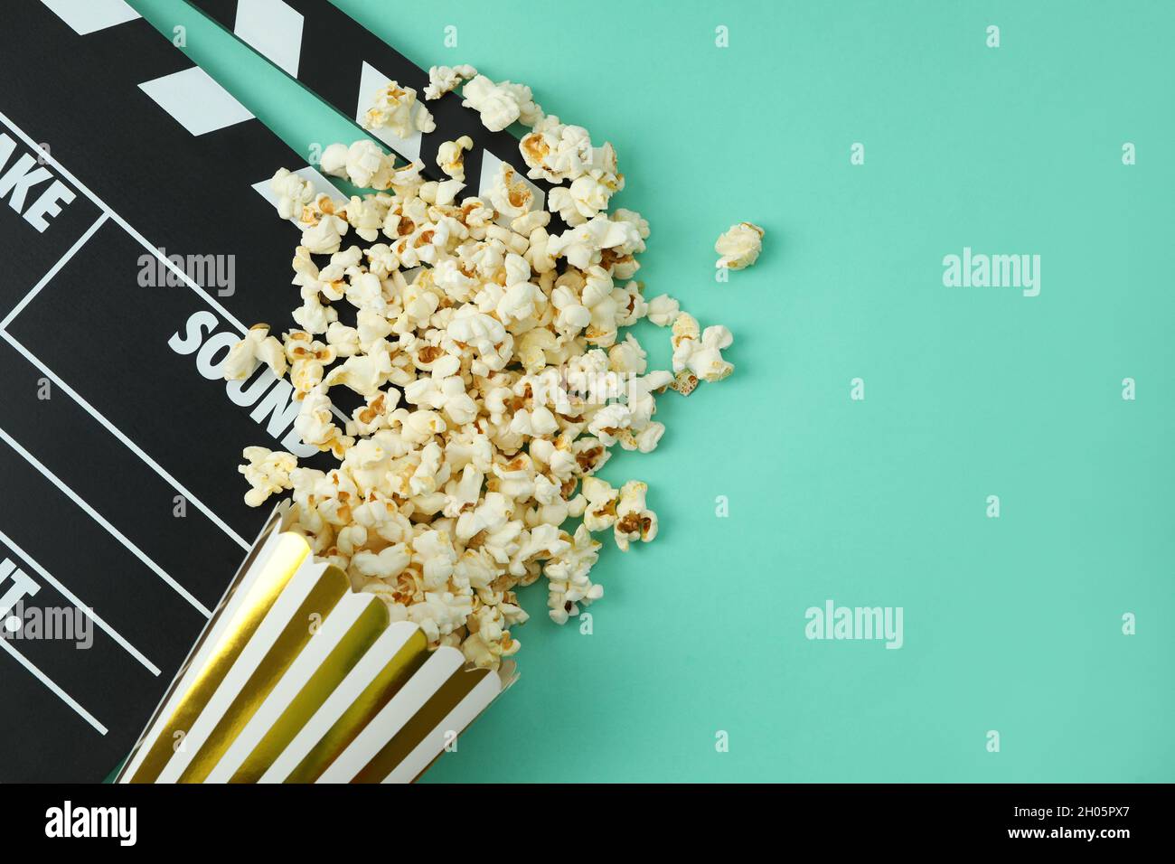 Сlapperboard and paper box with popcorn on mint background Stock Photo ...