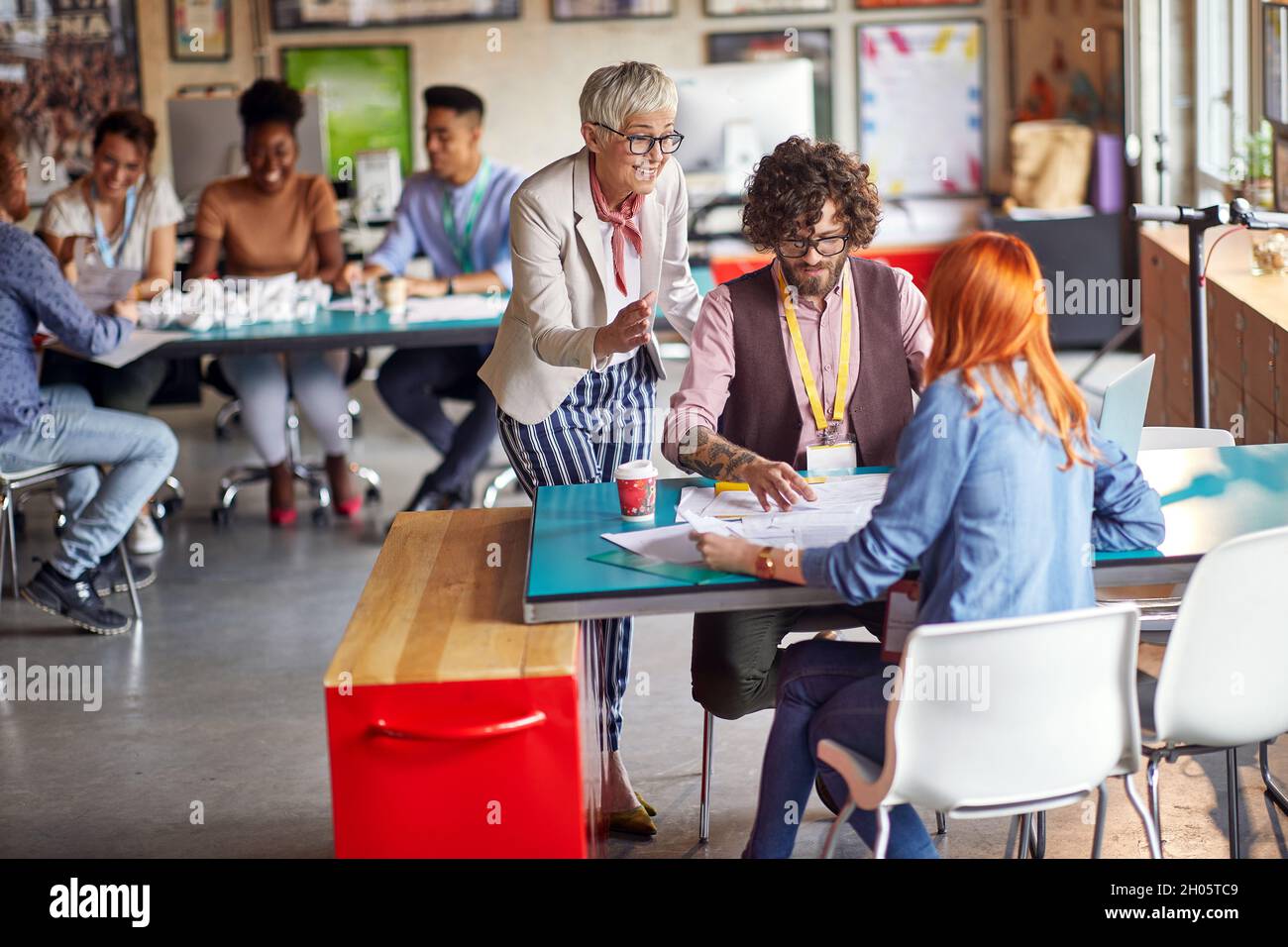 Senior colleague mentoring young employees at the office Stock Photo ...