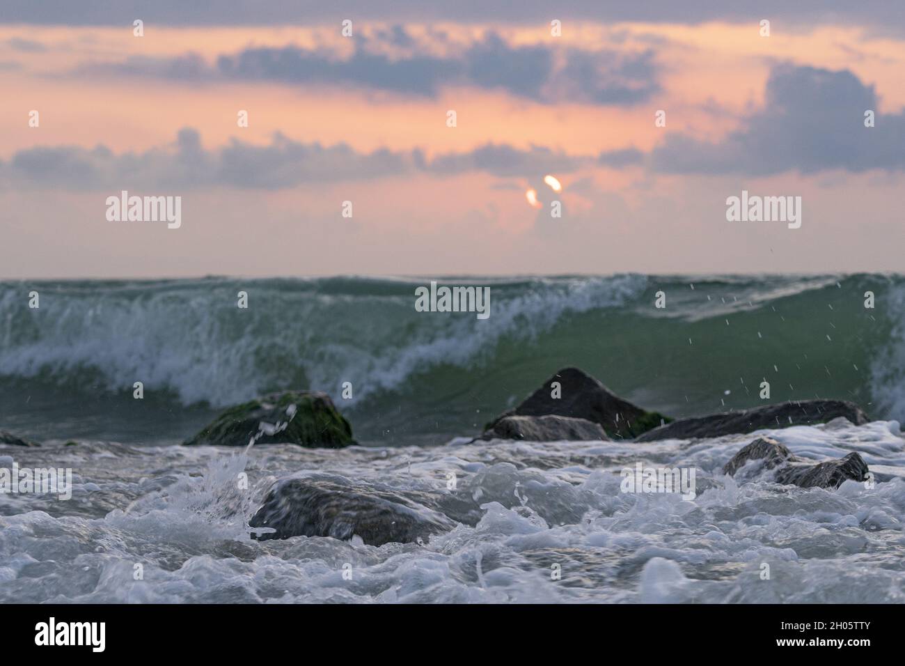 Sea waves crashing on the rock stones at sunset Stock Photo - Alamy