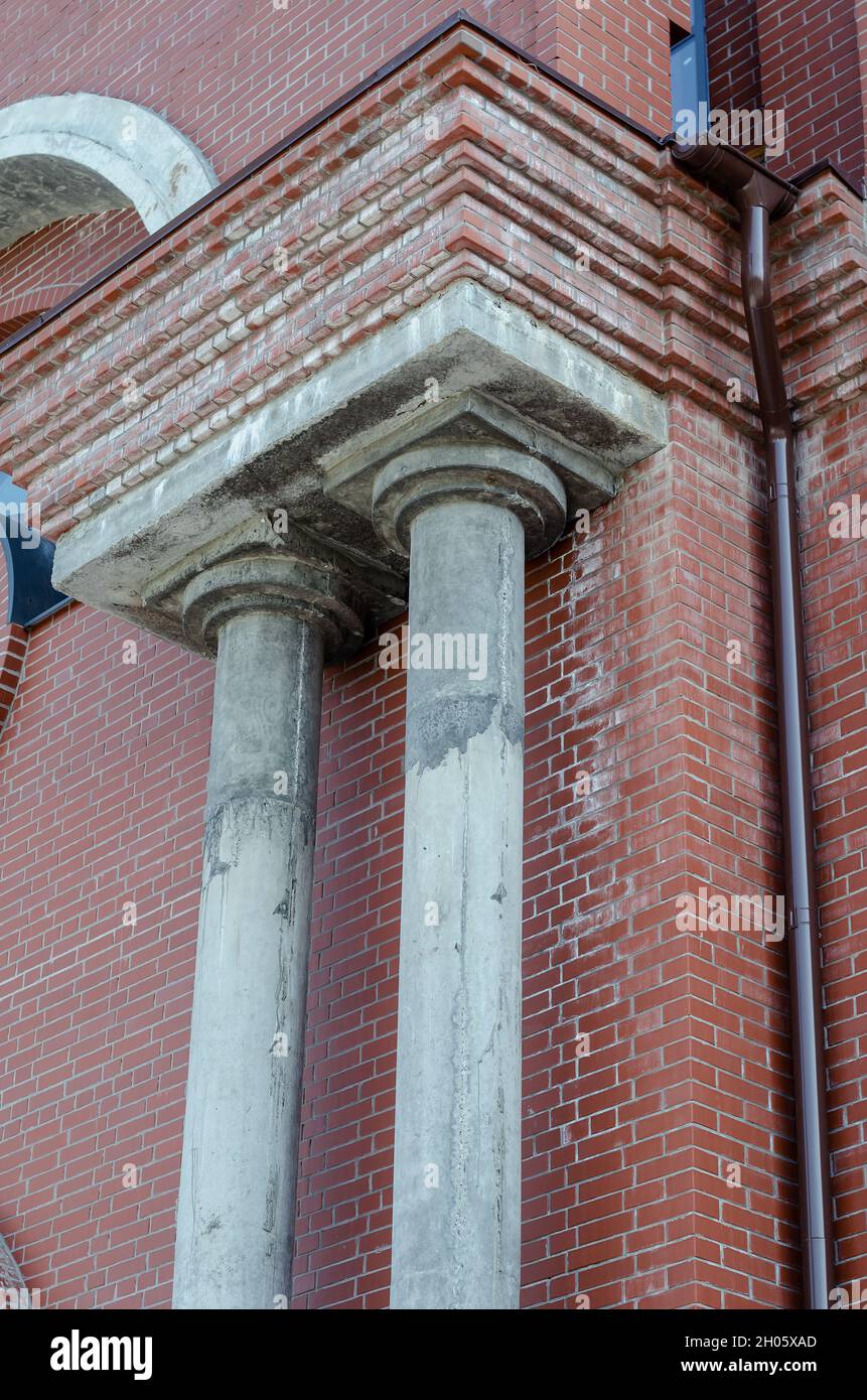 Red brick building with two gray columns. Concrete columns. Drainpipe ...