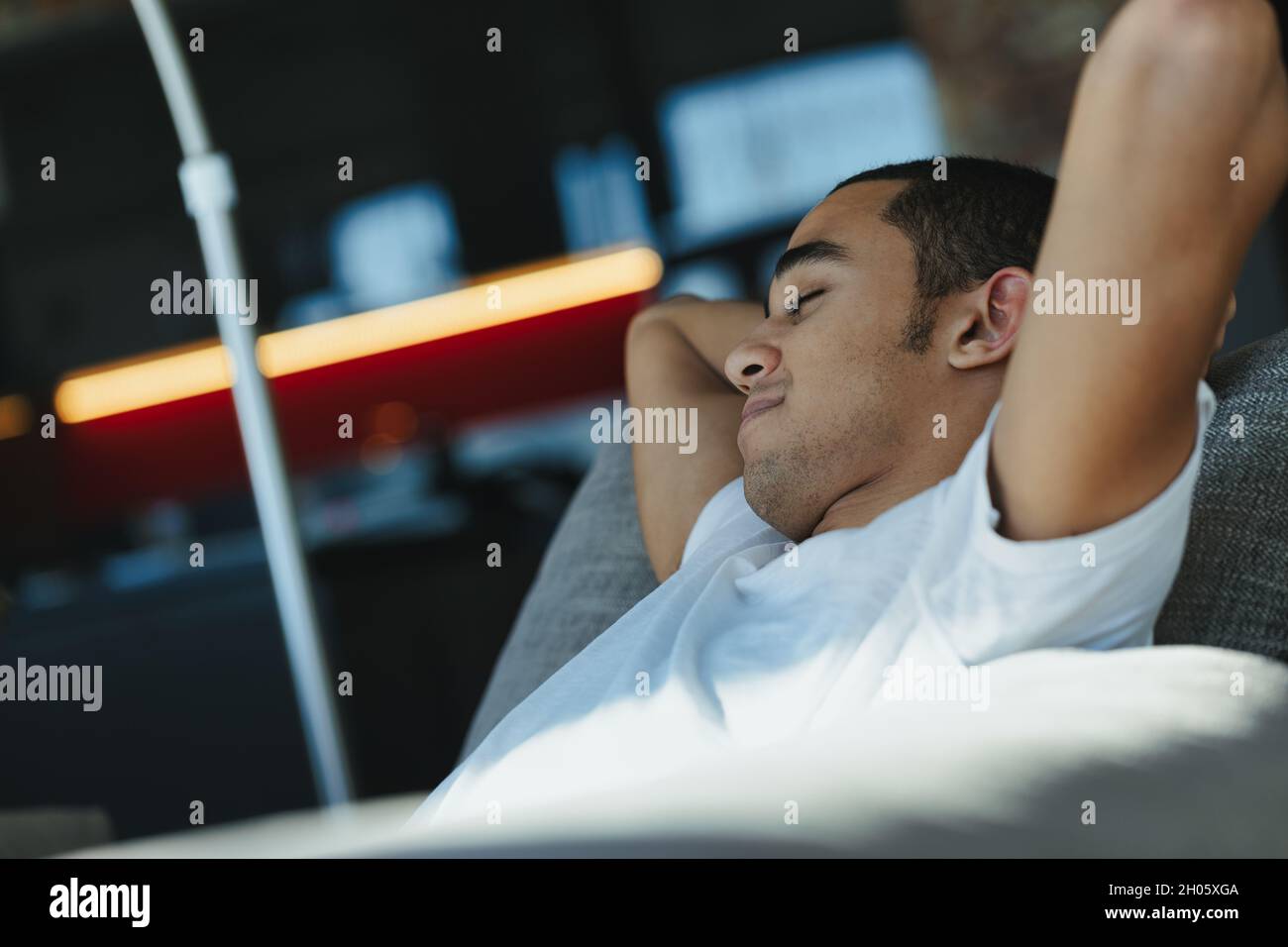 Tired young man snoozing in a comfortable chair with arms behind his ...
