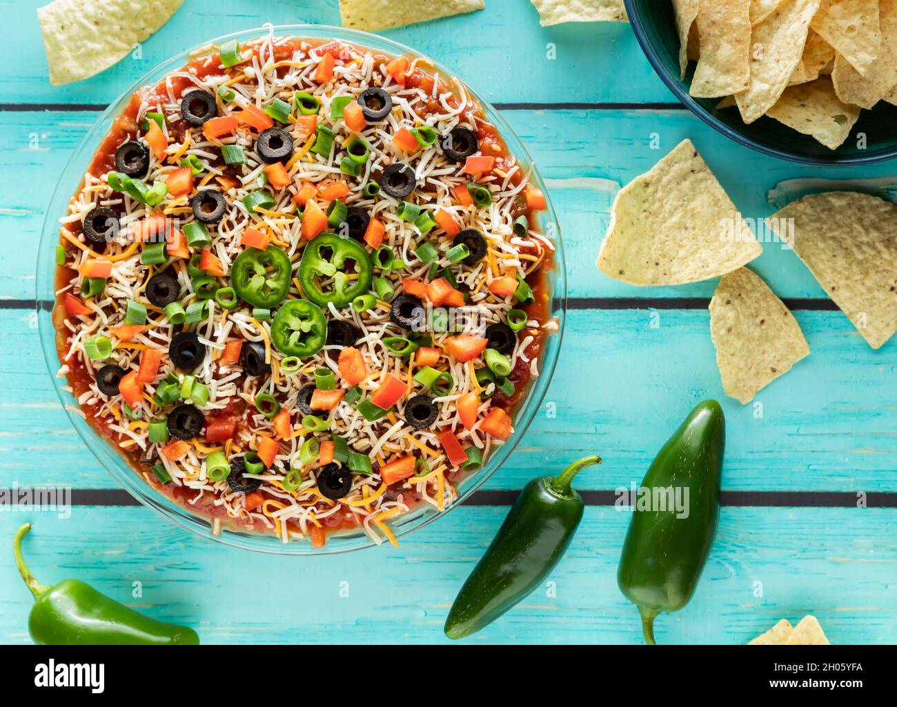 Top down view of a homemade 7 layer dip with tortilla chips ready for ...