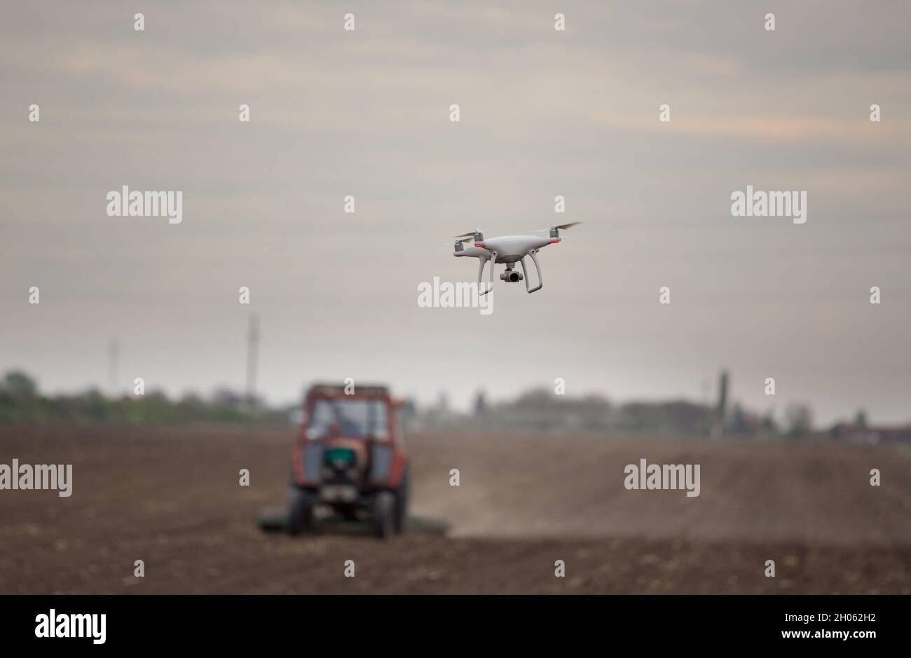 Drone flying above tractor with harrowing equipment in field Stock ...