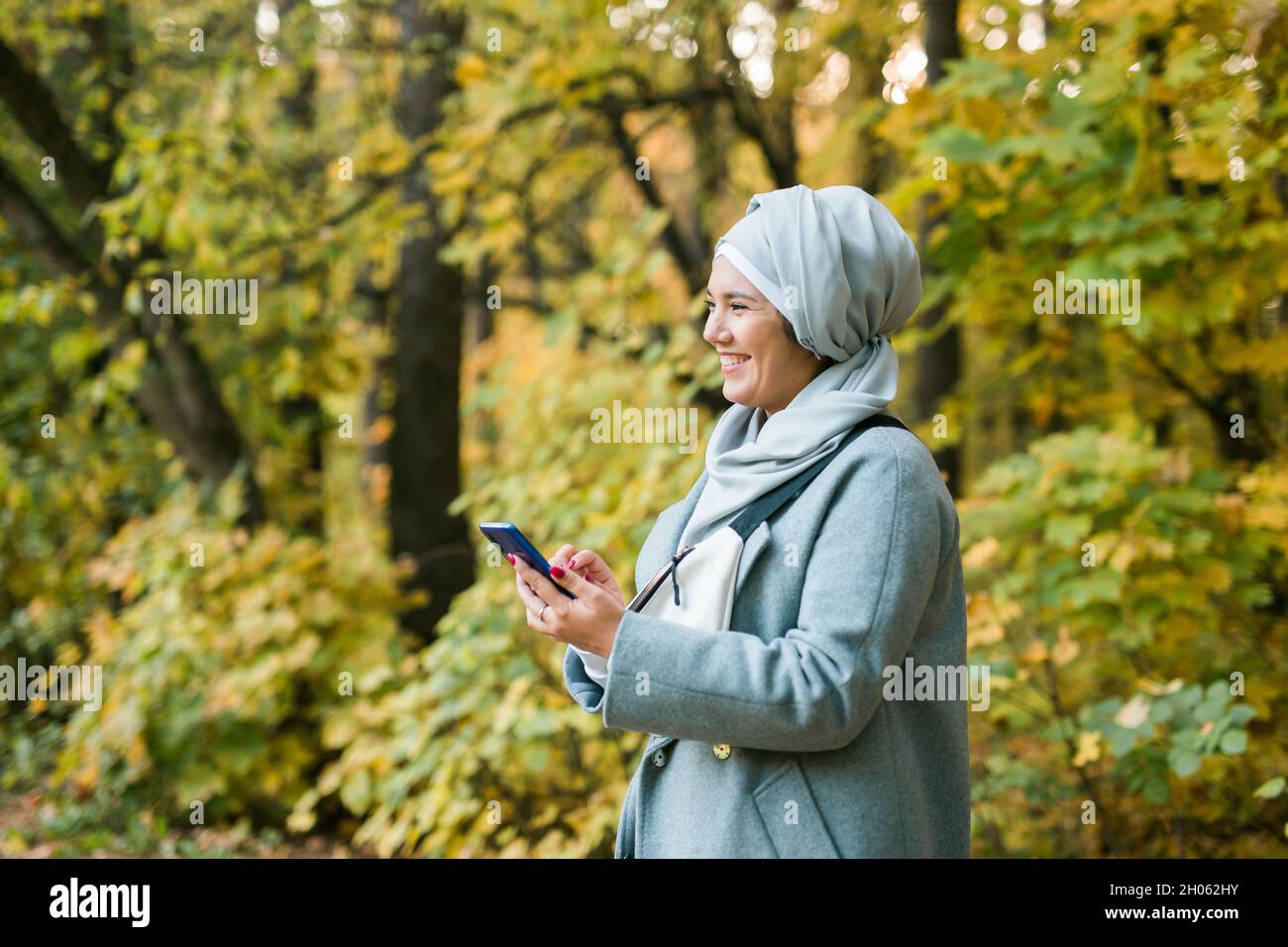 Pretty muslim woman using mobile phone outdoor. Arabic female wearing ...
