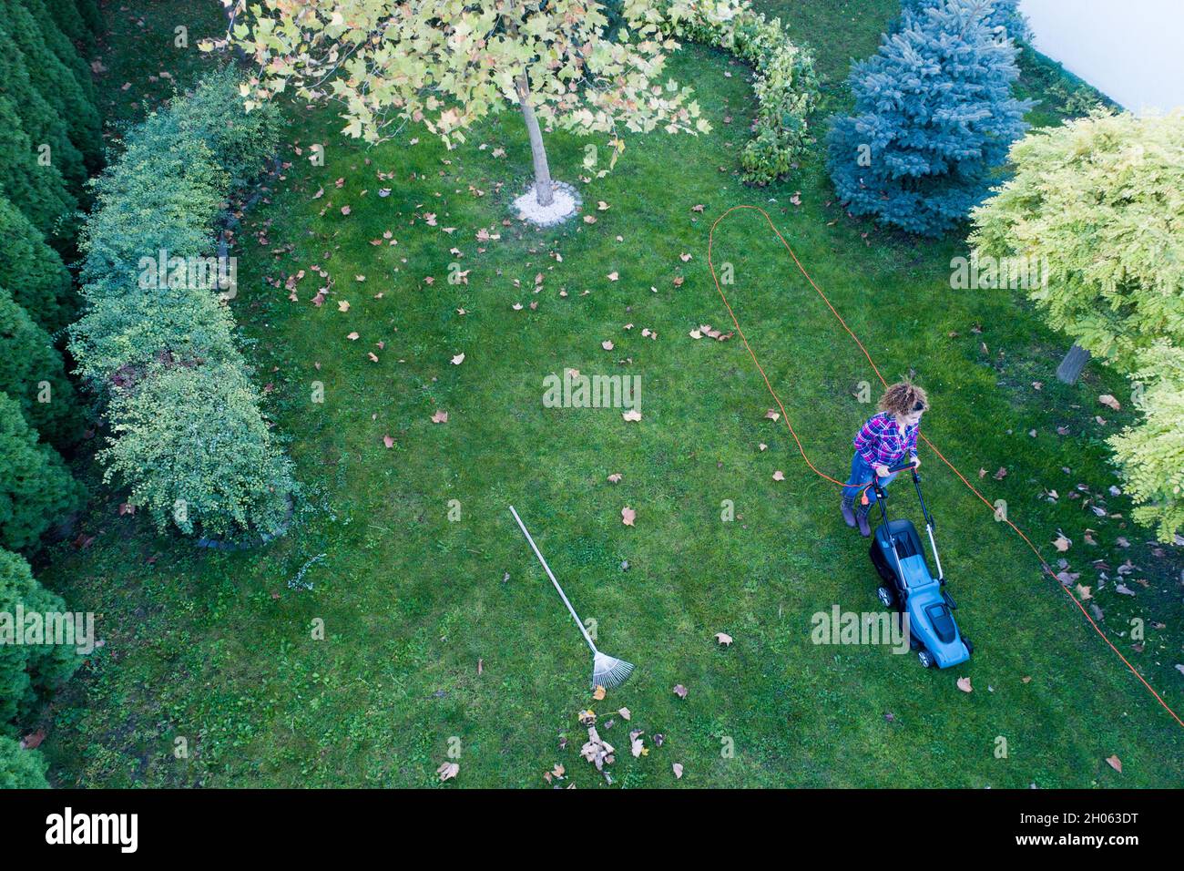 Aerial view of girl mowing lawn in backyard shoot from drone Stock ...