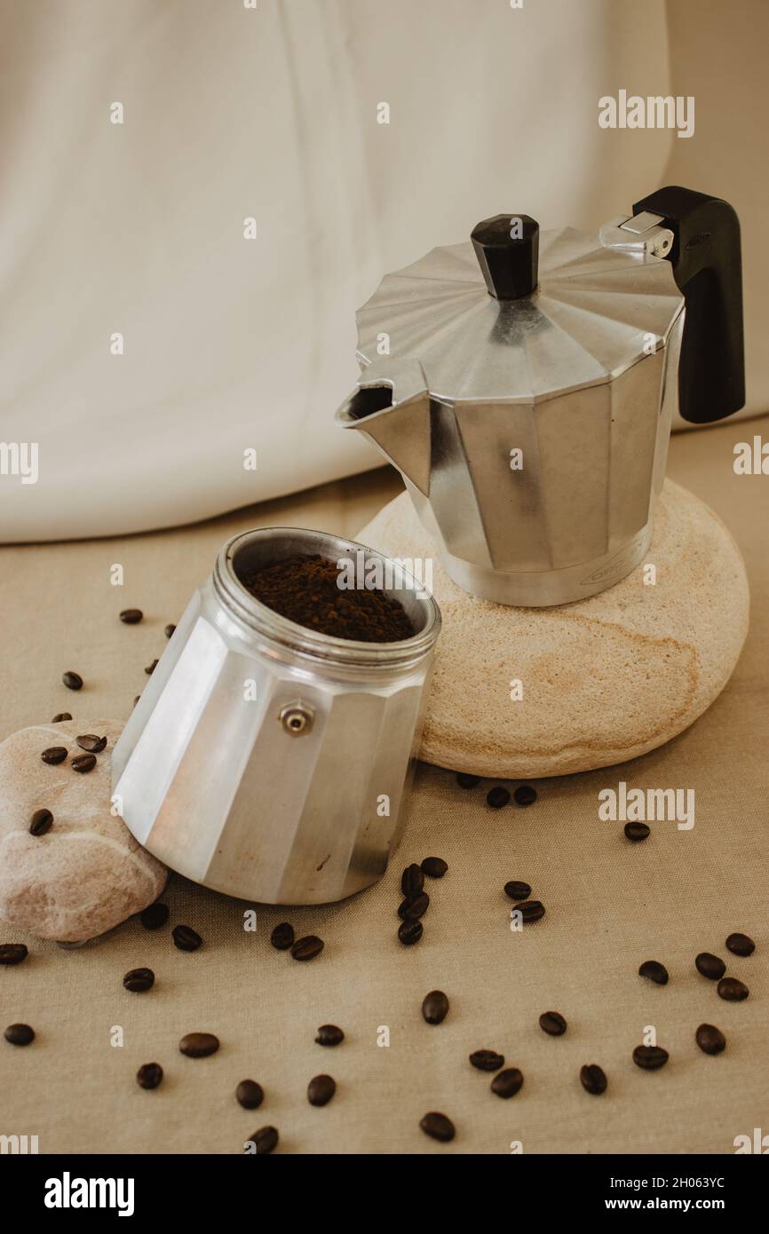 Metal coffee pot on a stone with coffee beans and coffee powder on an ...