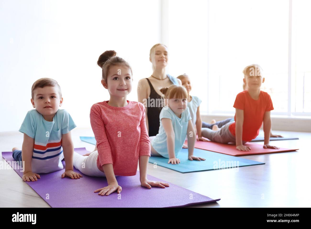 Little children and their teacher practicing yoga in gym Stock Photo ...